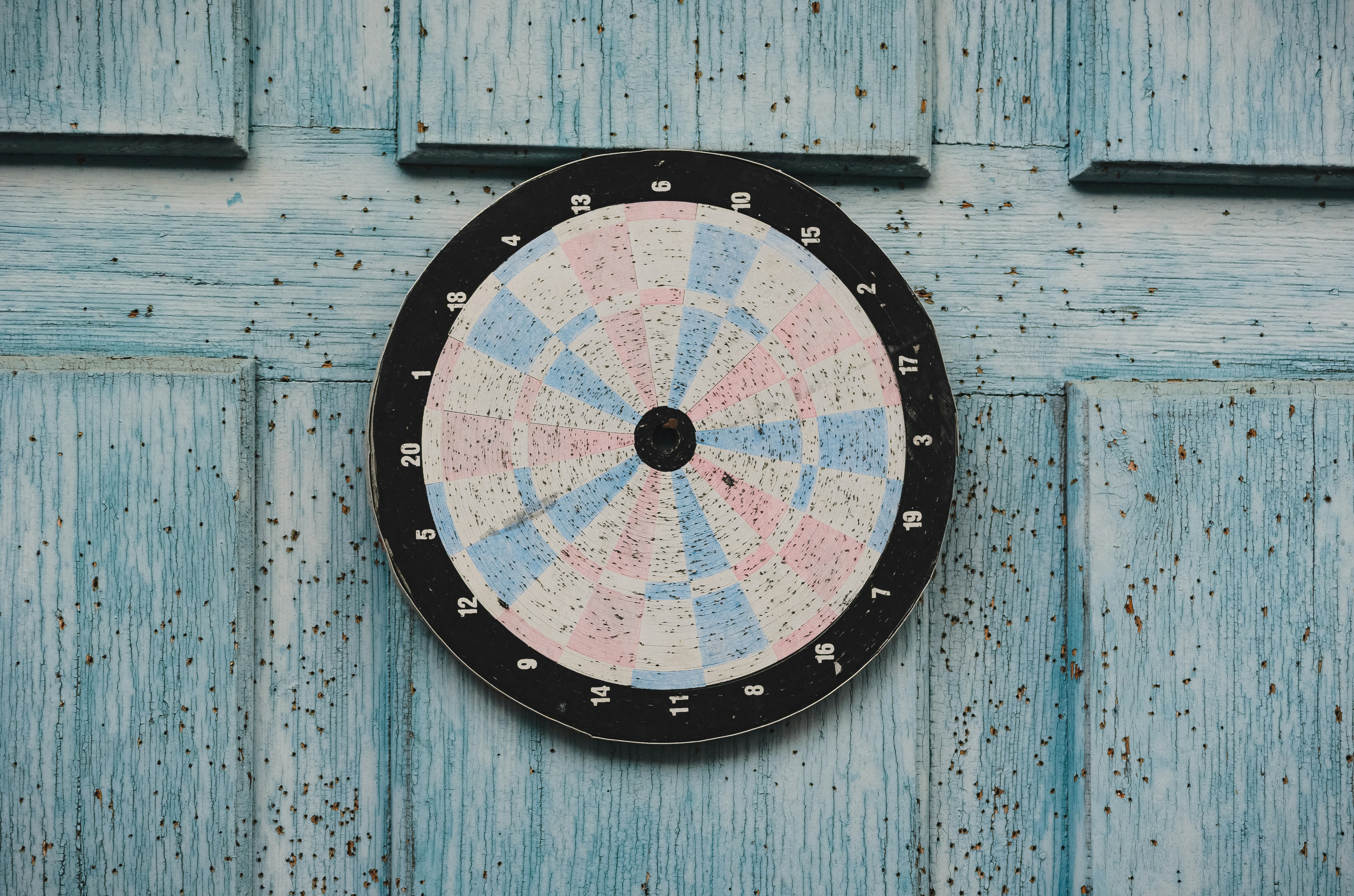 Target in Focus: A Weathered Dartboard on a Pale Blue Door