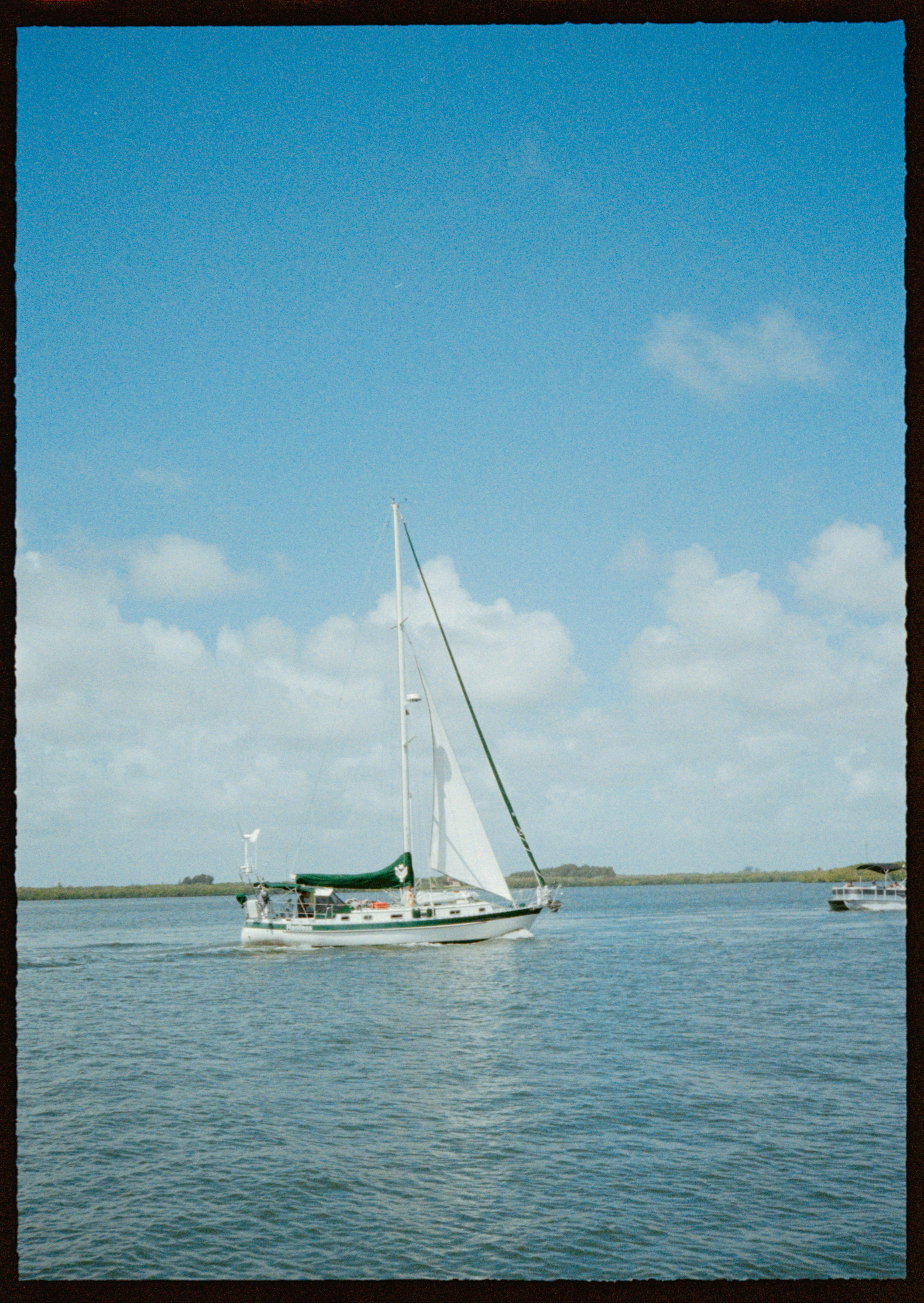 Sailboat gliding on calm blue water under a clear sky