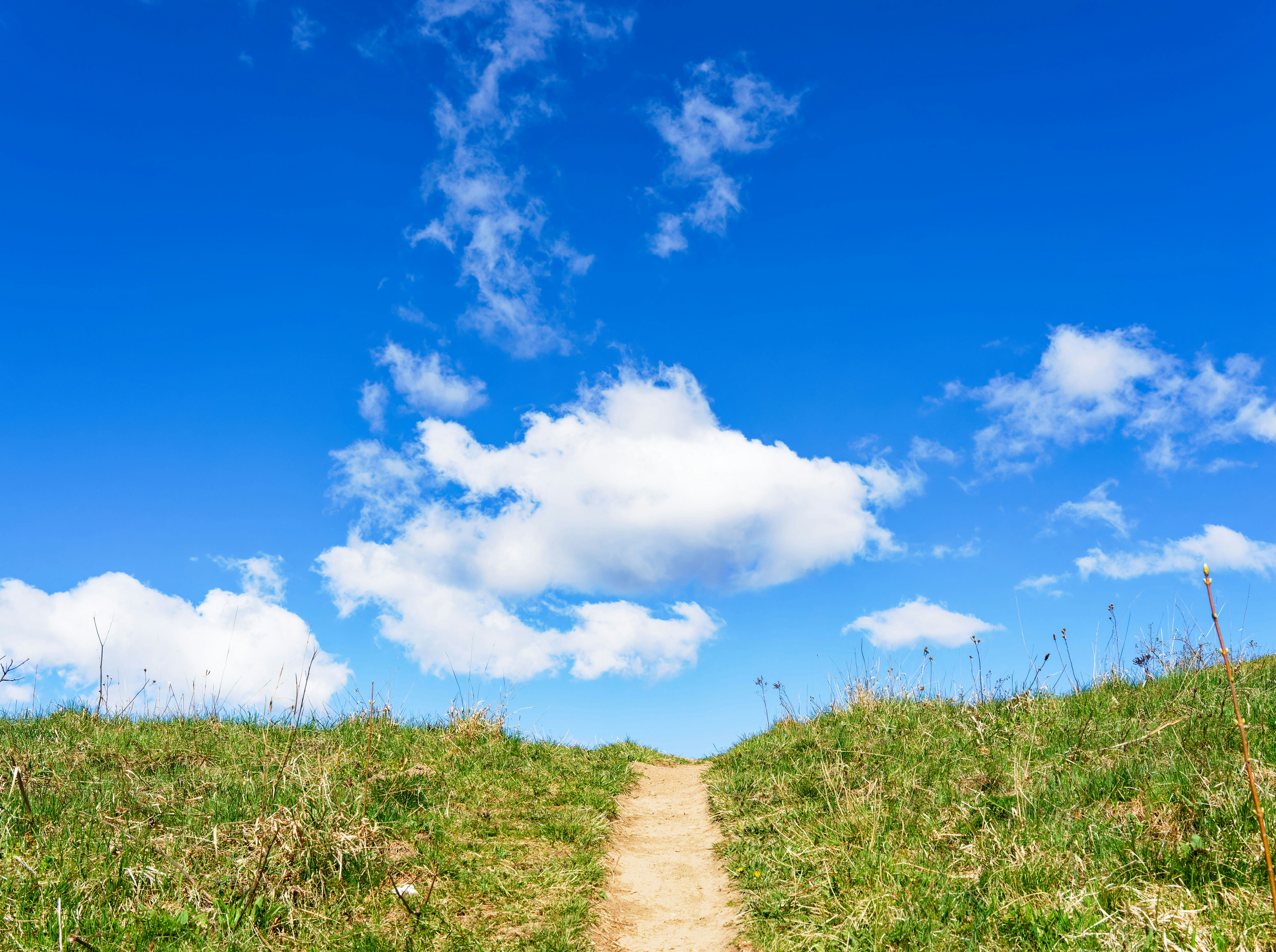 Path to the Crest: A Sunlit Hill Under a Wide Blue Sky