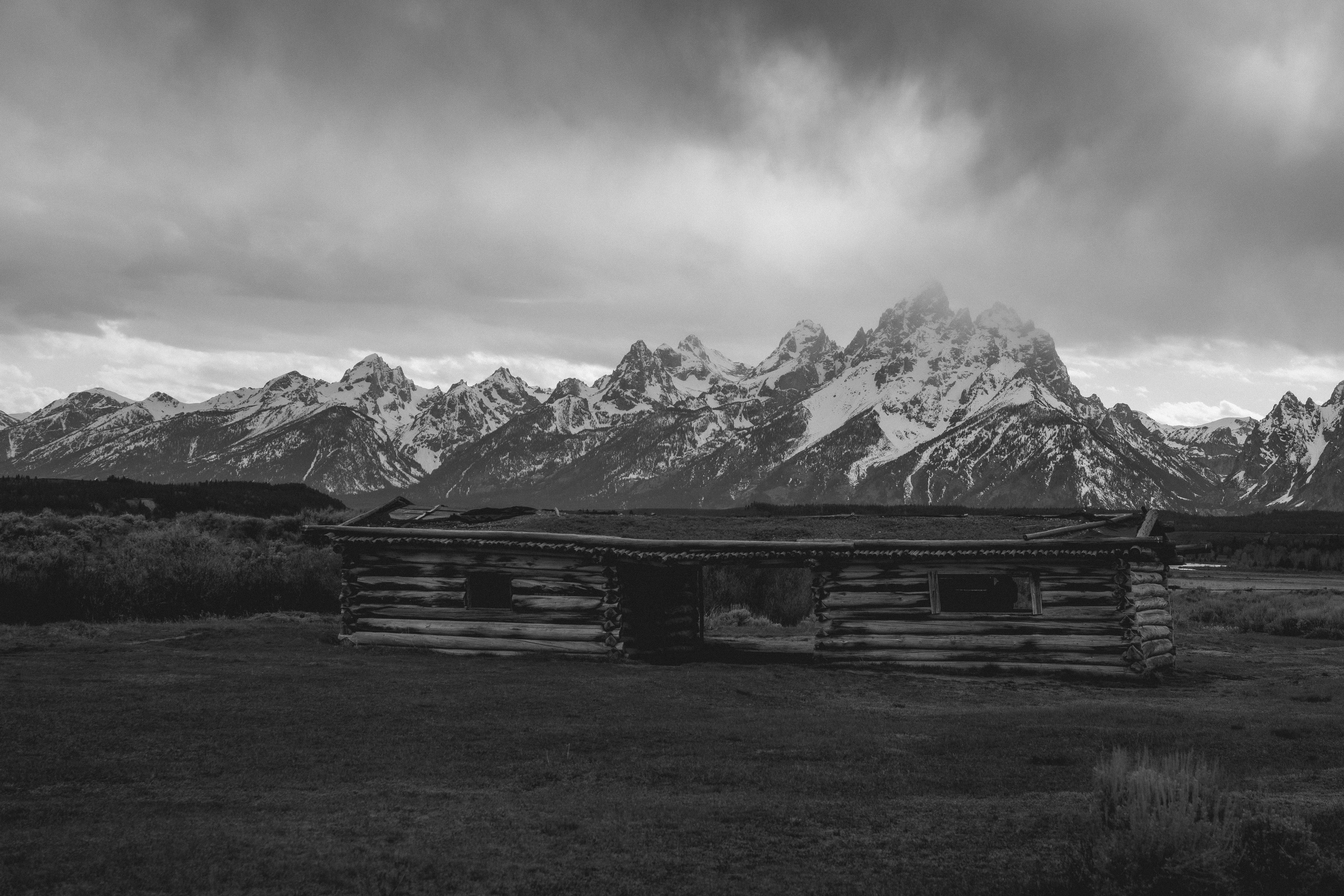 Winter Span: A Lone Log Cabin Beneath Jagged Peaks