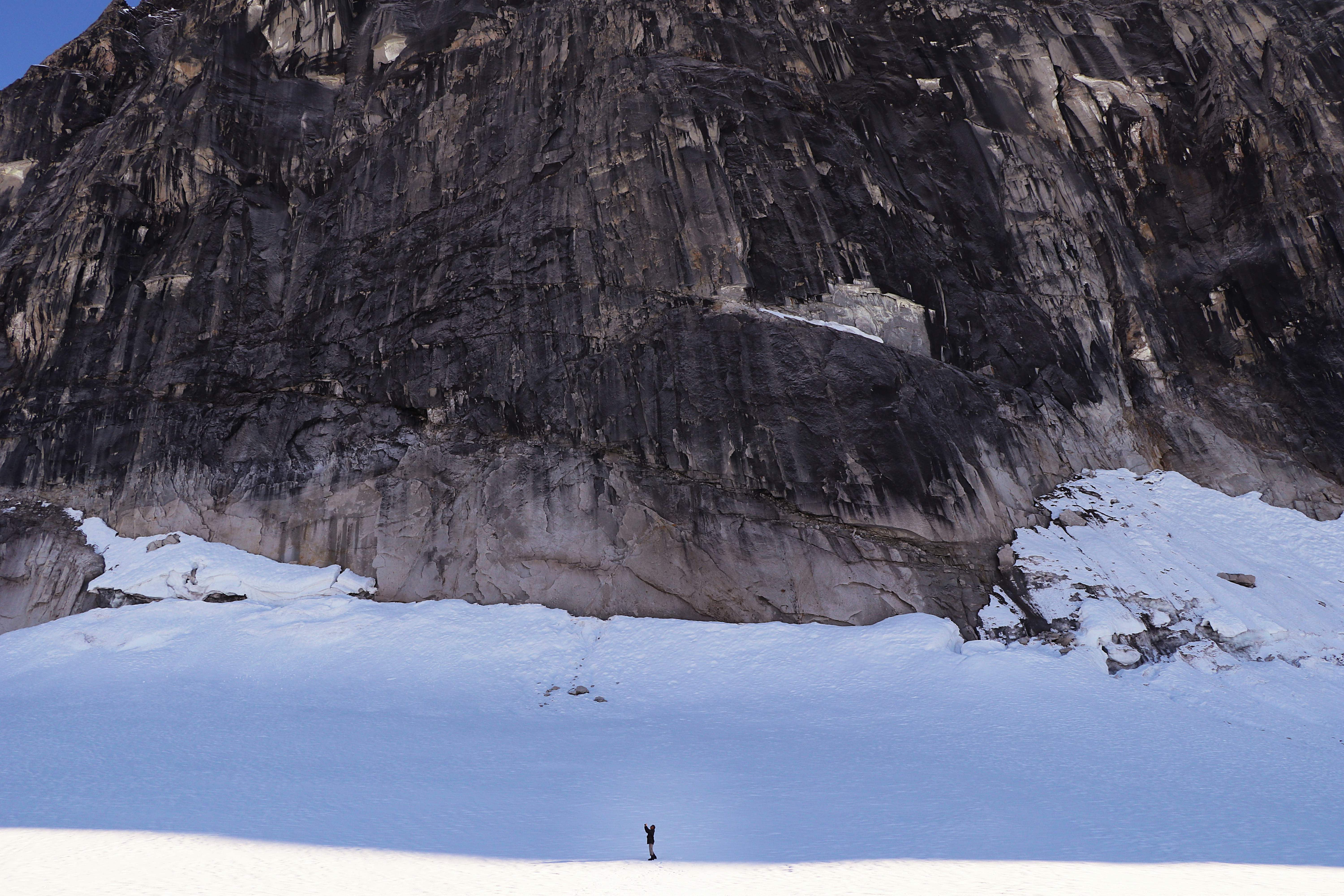A Lone Figure at the Base of a Snowbound Cliff