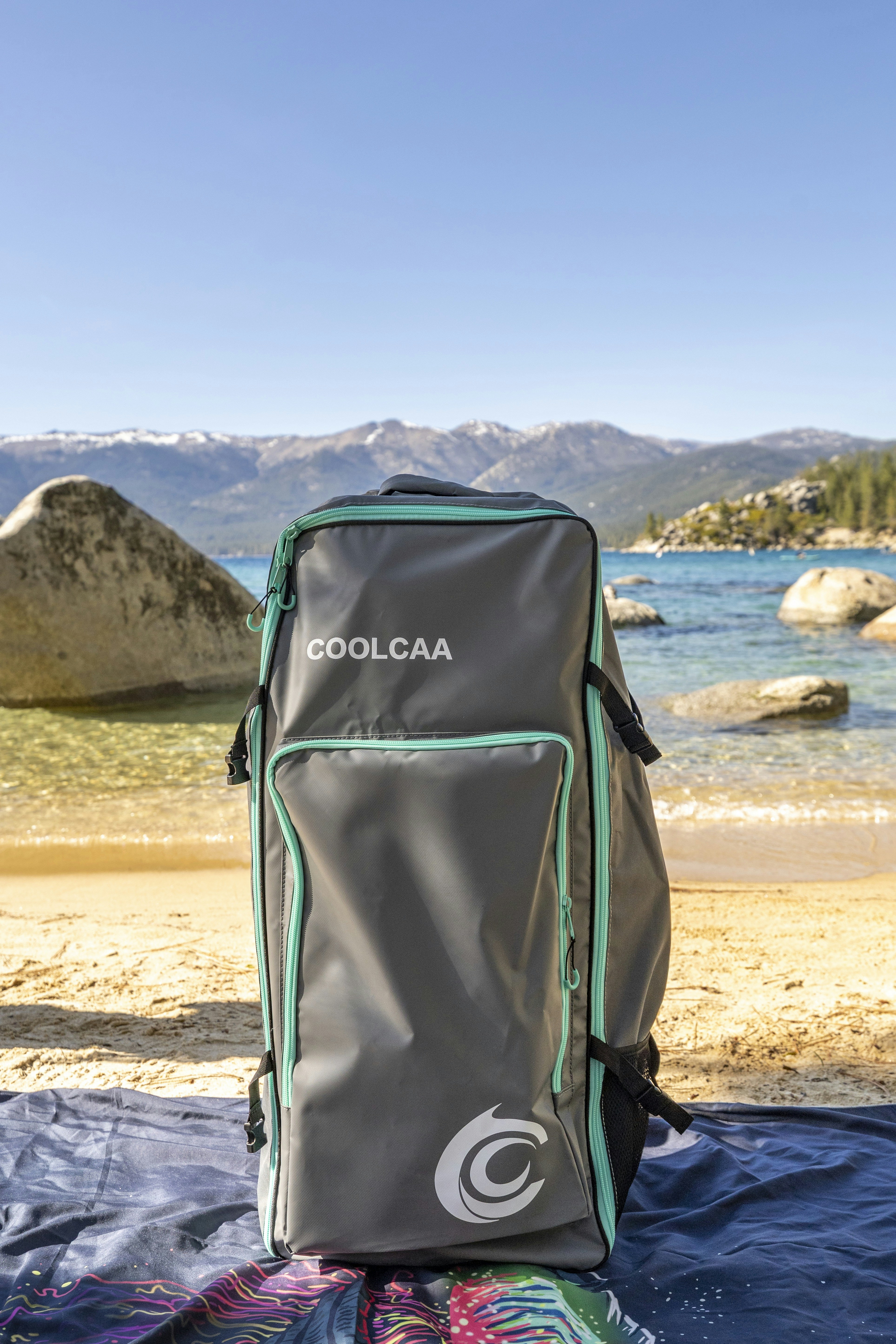 Backpack by the Lake: teal-zip backpack with COOLCAA logo set against alpine shoreline
