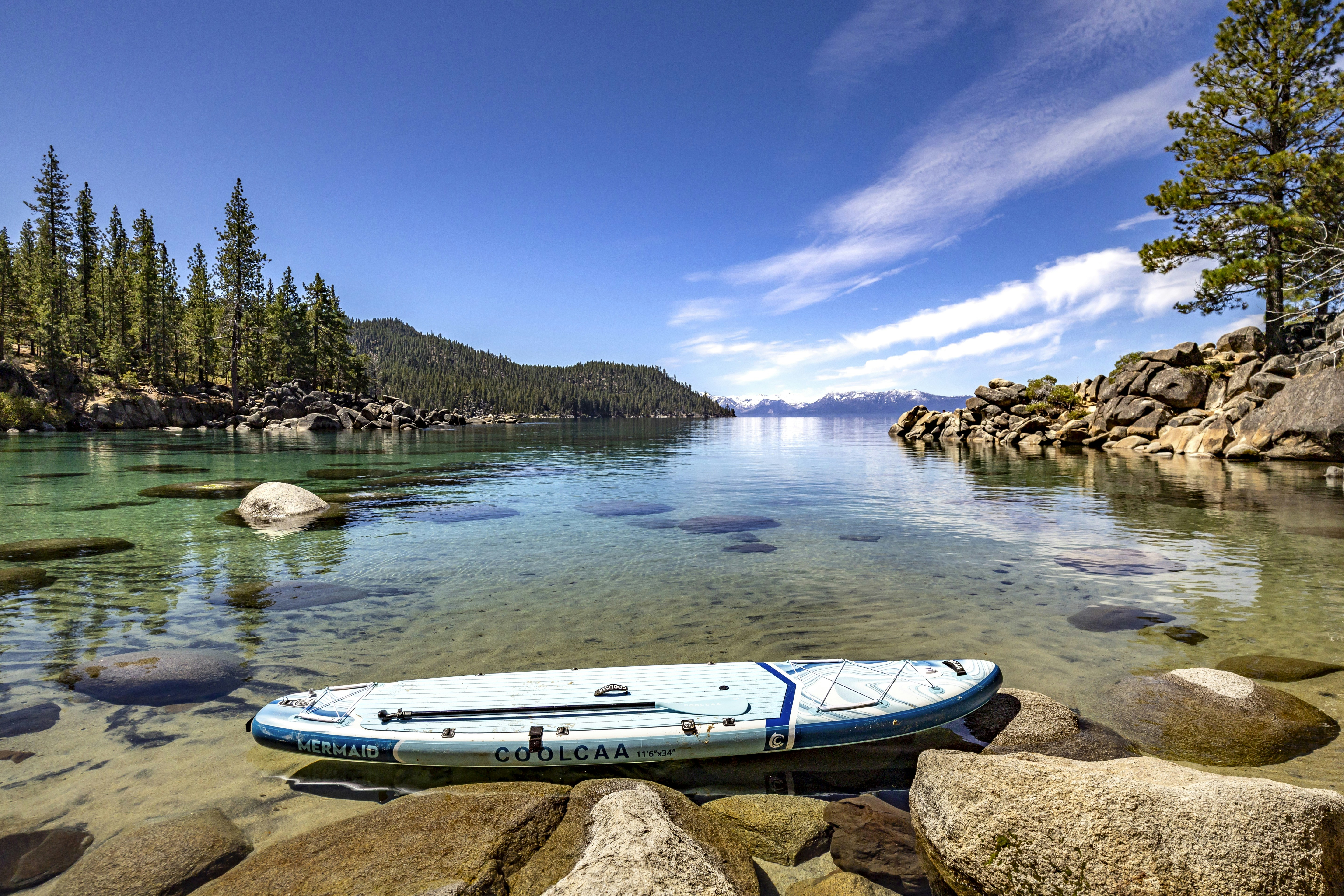 Calm Dawn at Emerald Cove: Paddleboard Resting on Rocky Shore