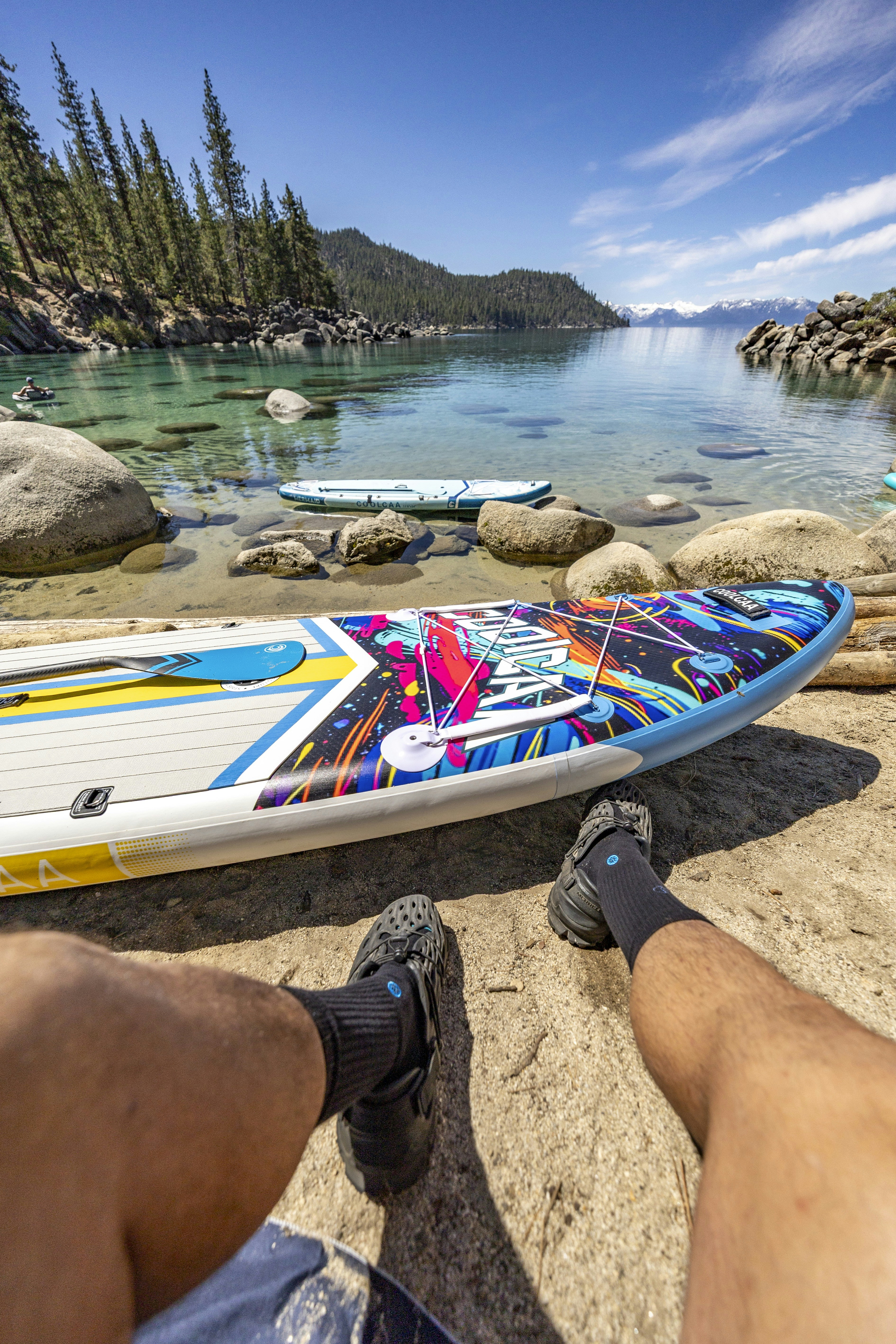 Sunlit Shoreline Rally: Paddles, Rocks, and Colorful Boards