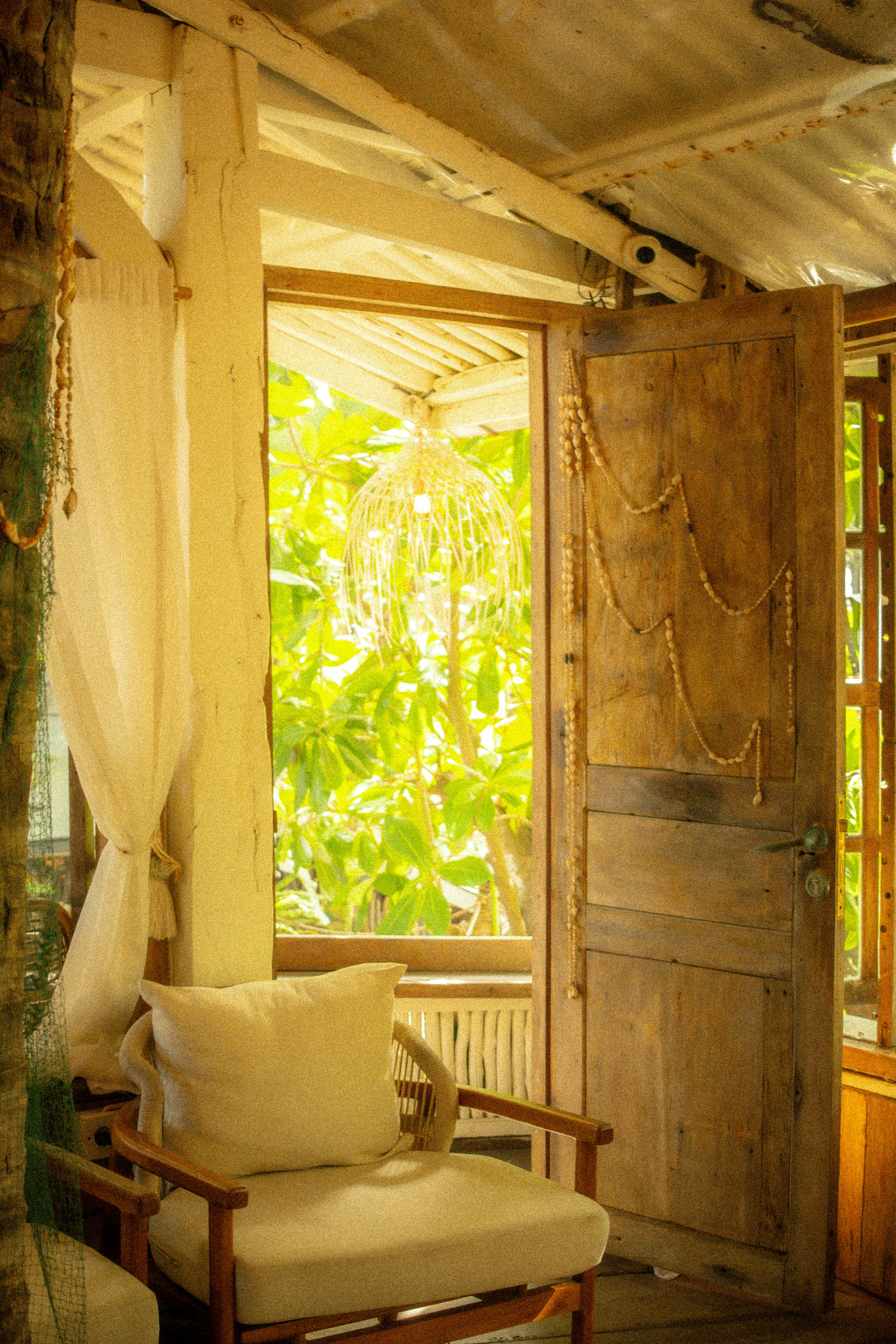 Sunlit Porch Cozy: A Rustic Armchair by Open Doors to Greenery