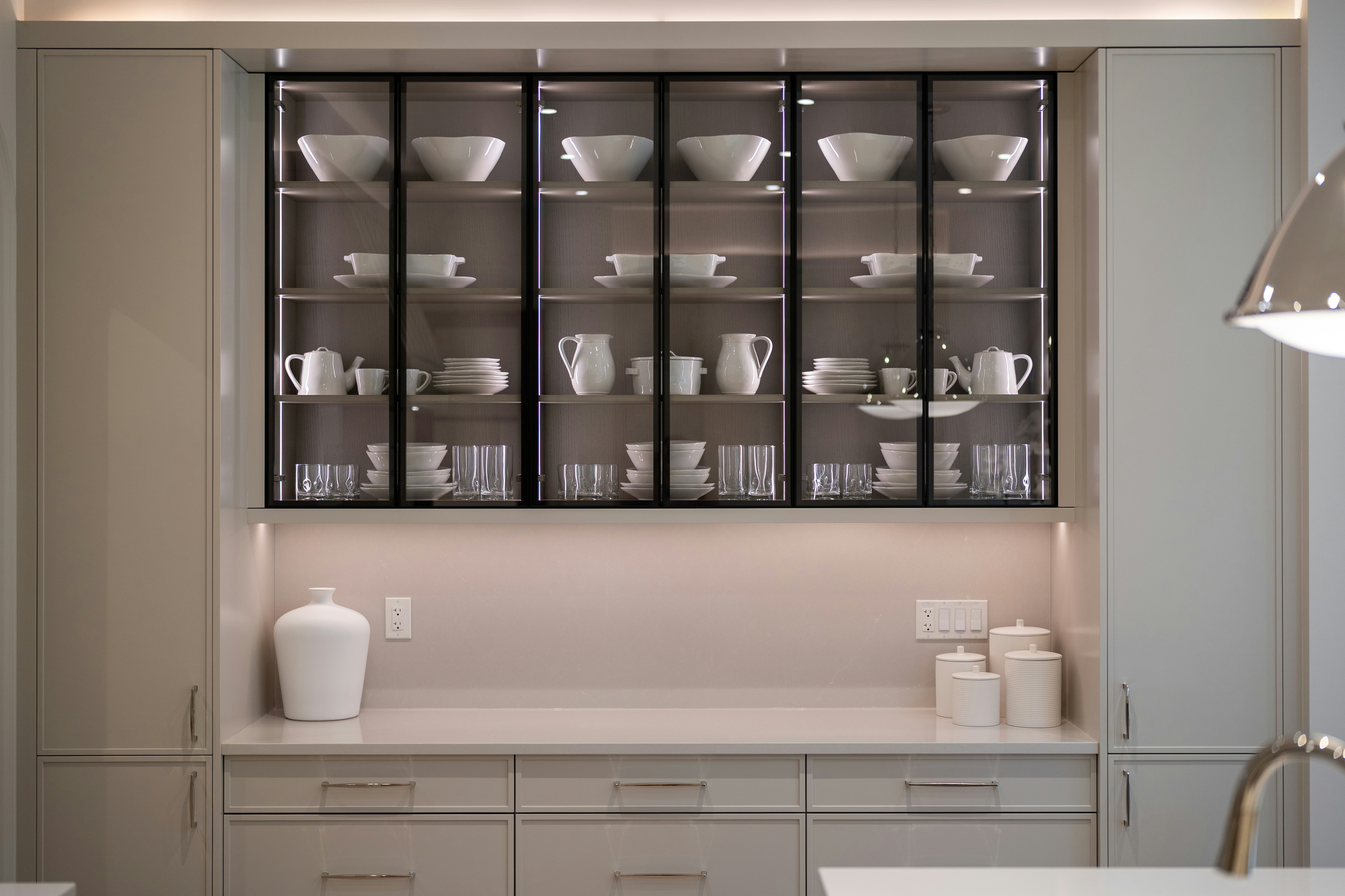 Hidden symmetry: A glass-fronted dish cabinet over a pale kitchen counter
