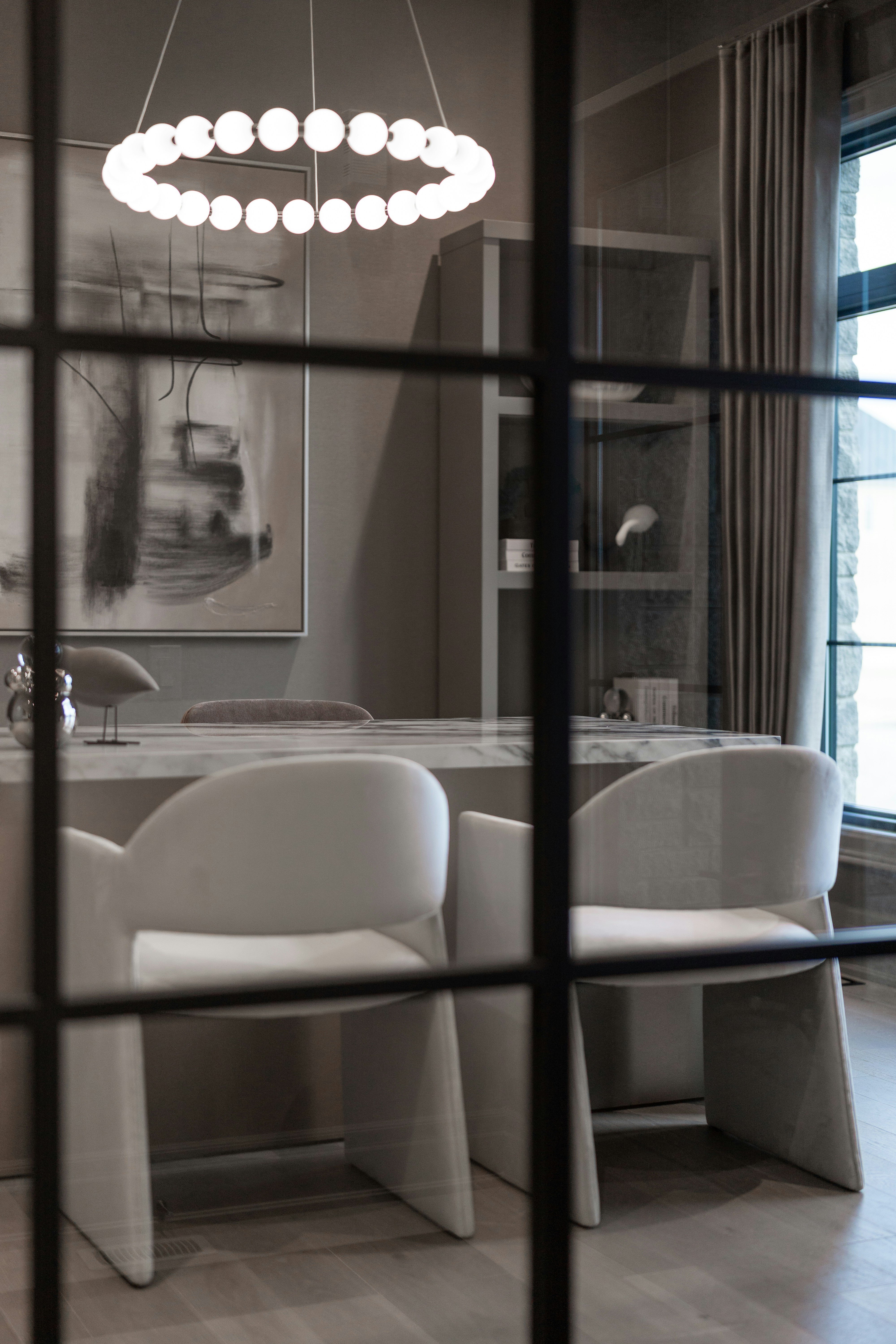Modern dining room through black window grids with circular pendant light