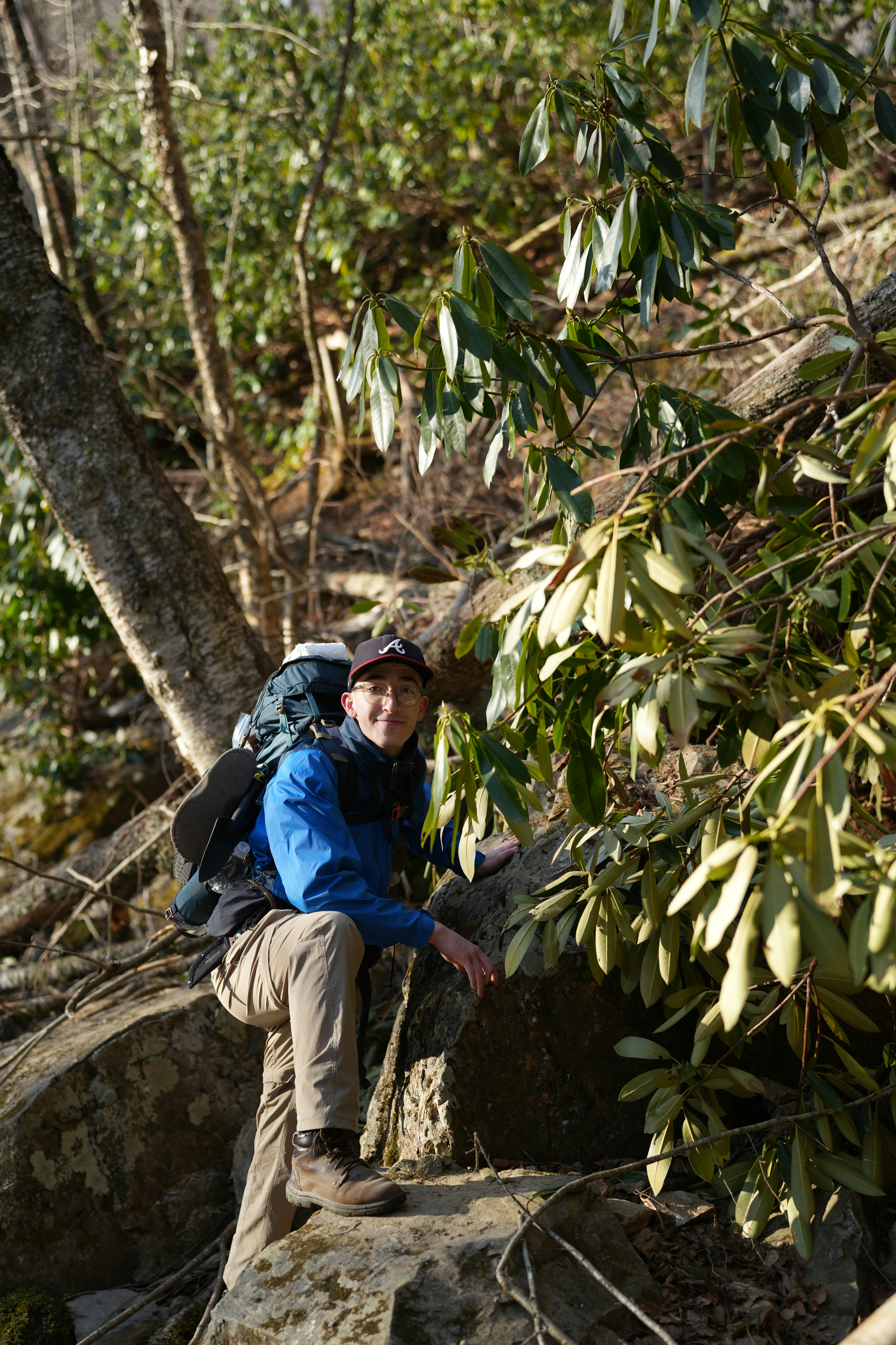 Hiker Reaching for a Climb Among Mossy Rocks