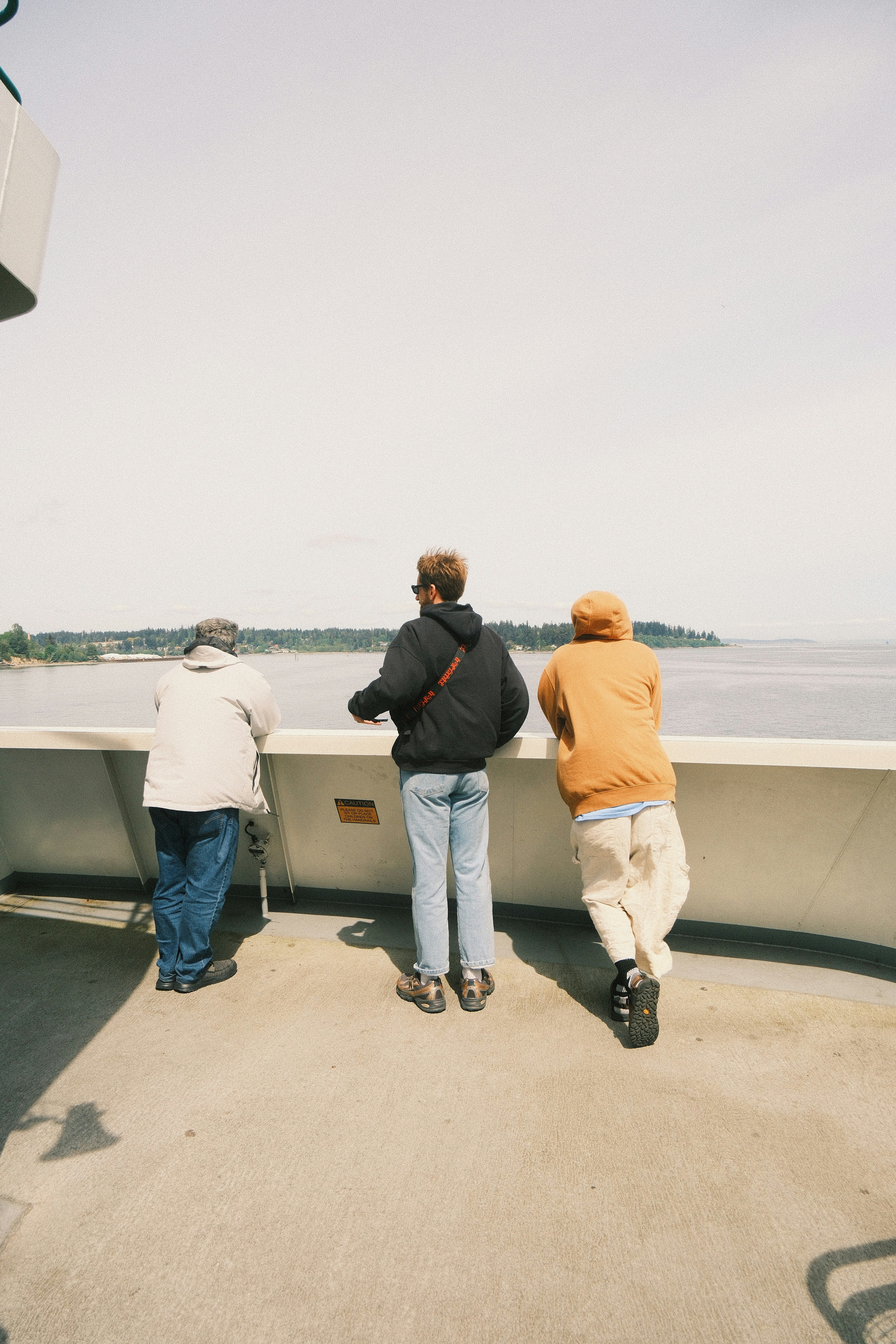 Three Figures on a Waterfront Rail, Gazing Toward the Distance