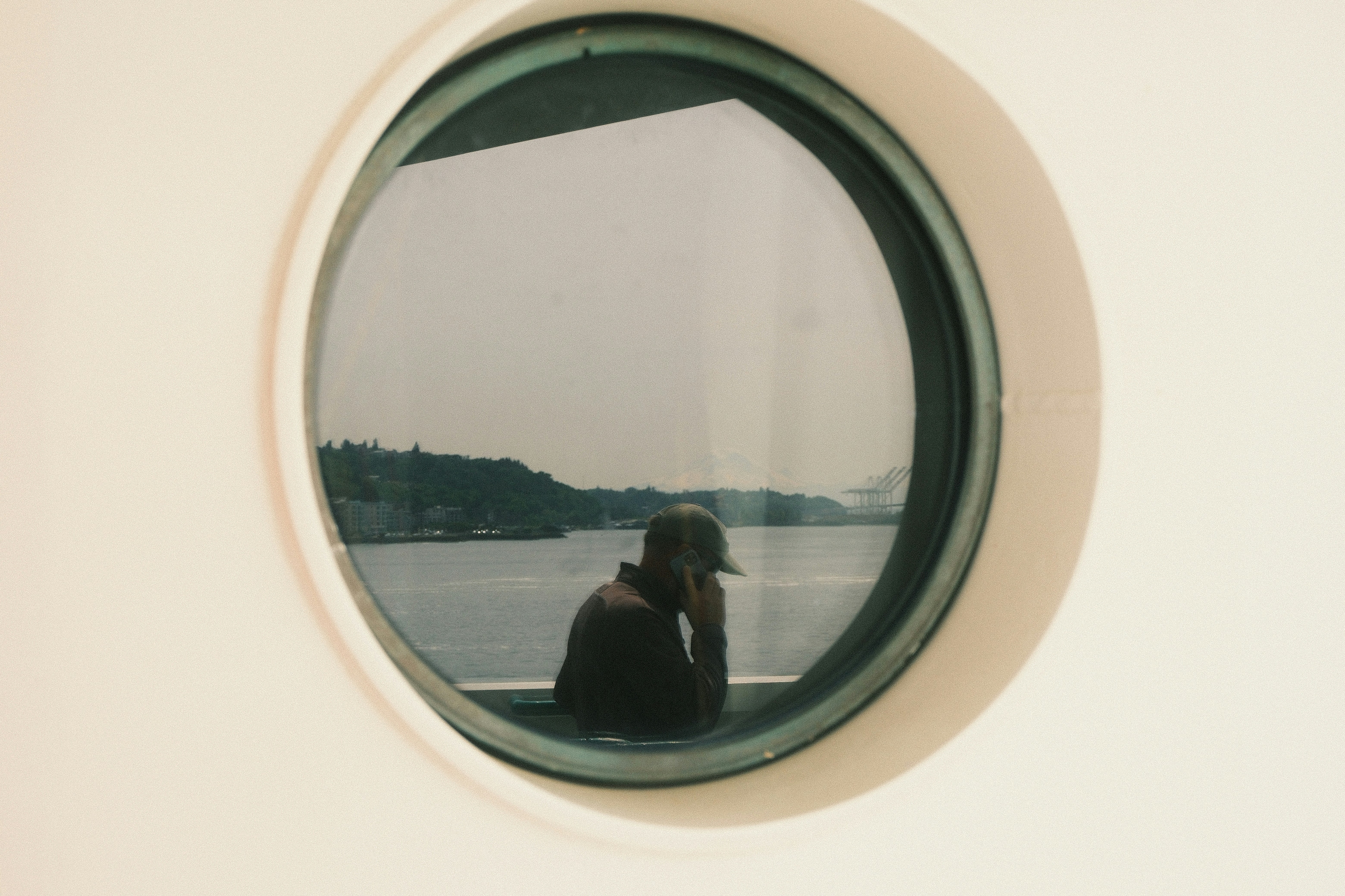Circular View: A Solitary Figure Reflected in a Ship Window