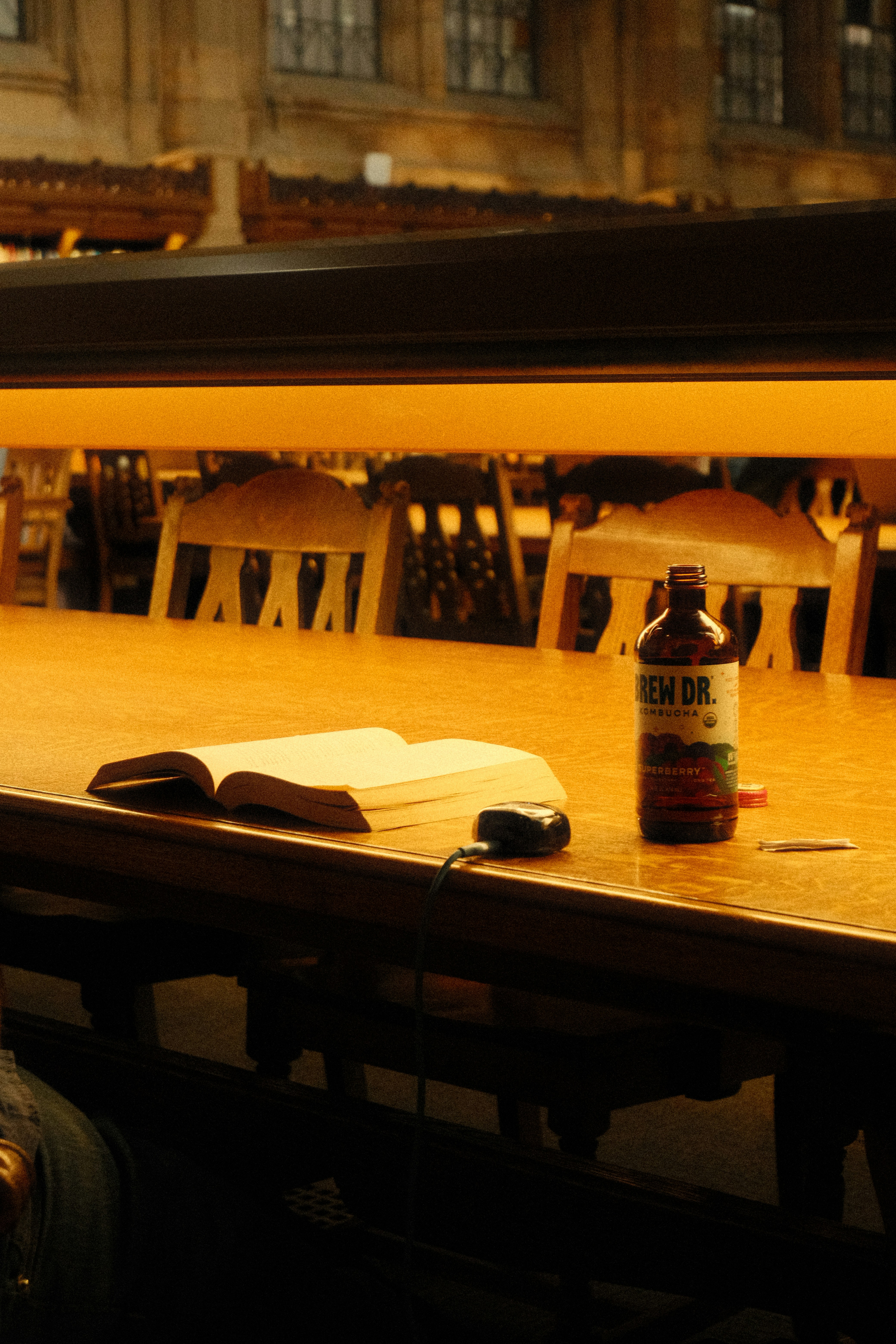 Open notebook, bottle of brew, and a single corded object anchor a quiet cafe moment