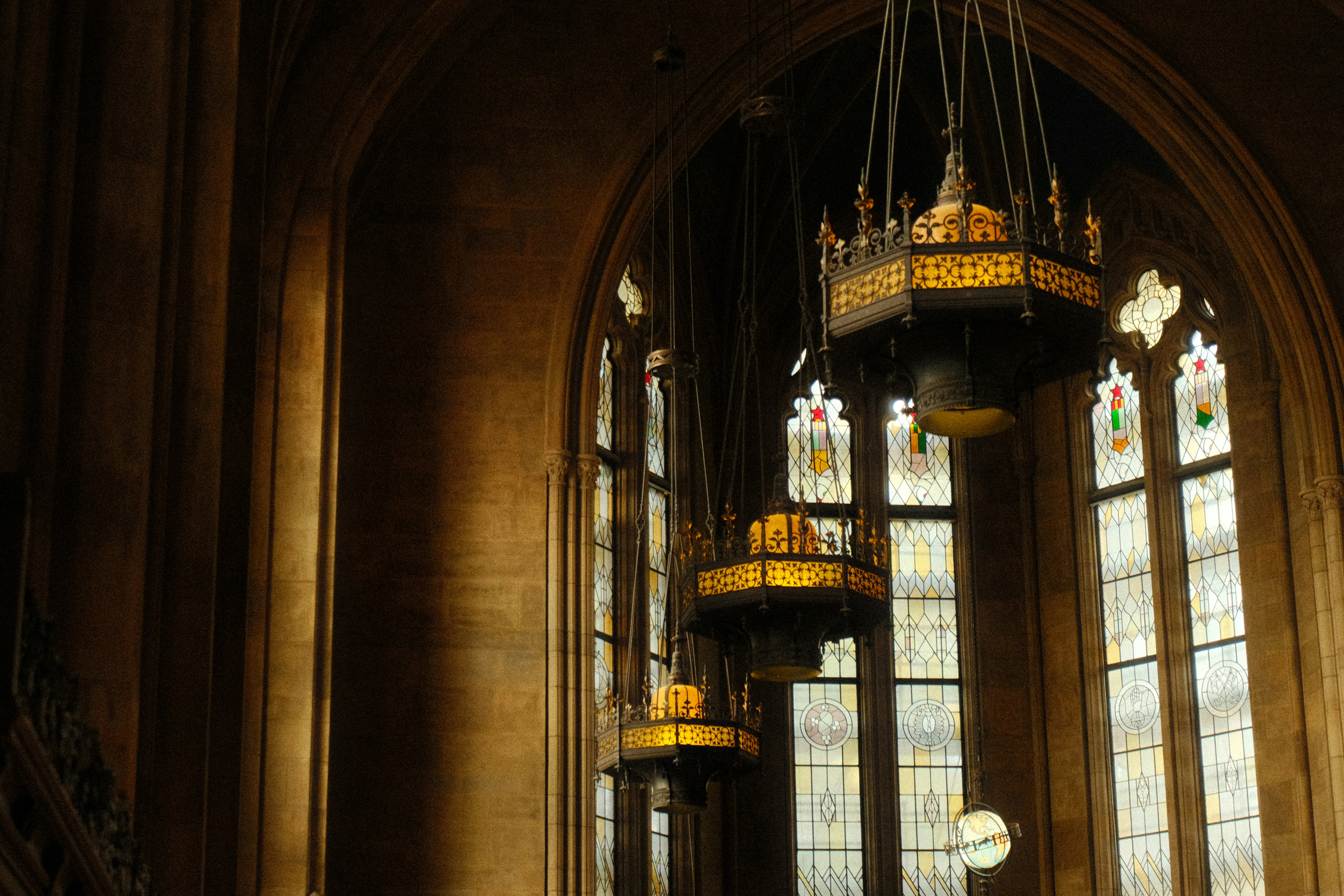 Golden chandeliers drinking light in a Gothic nave