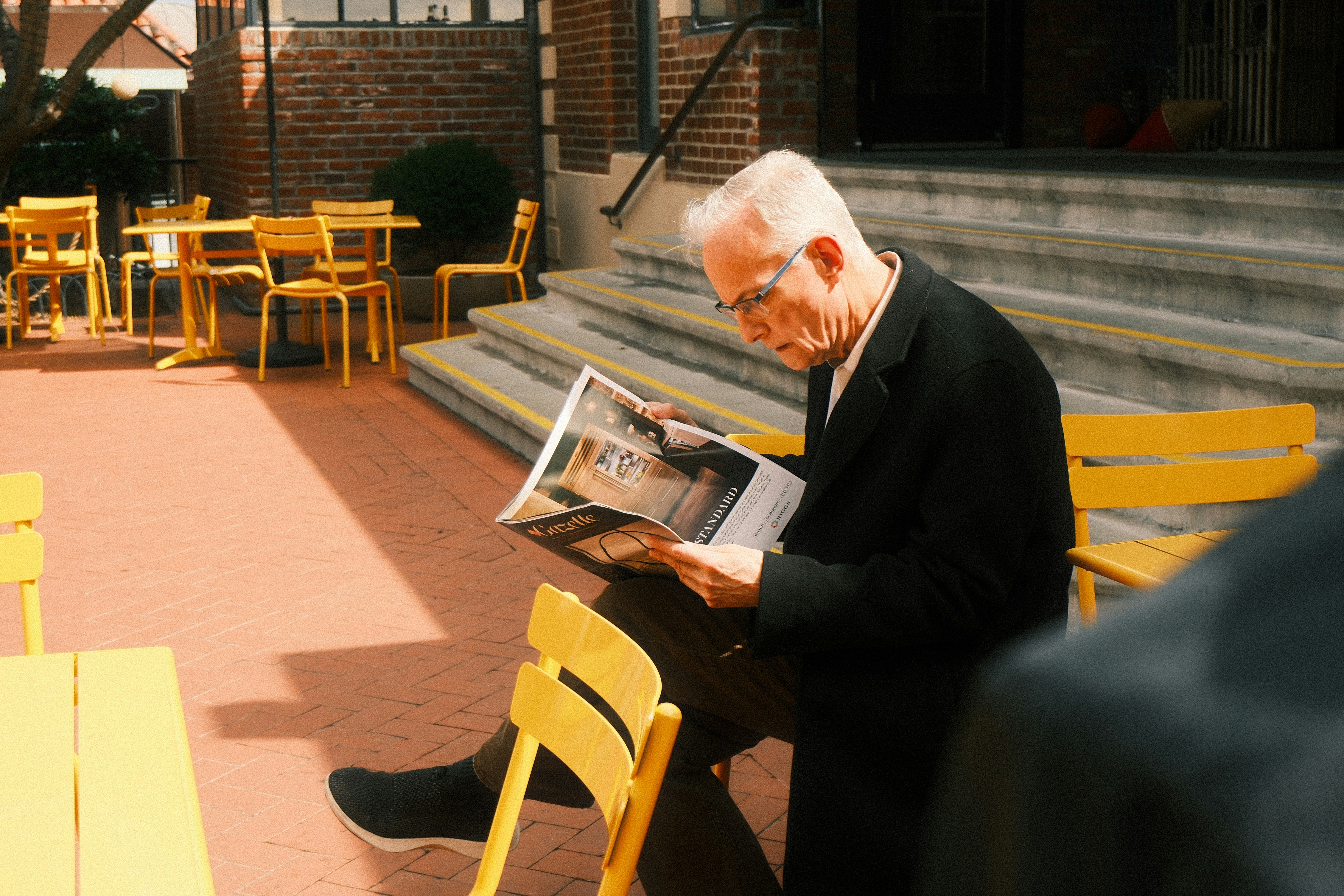 A Quiet Moment: Elder Gentleman with Newspapers in the Outdoor Café