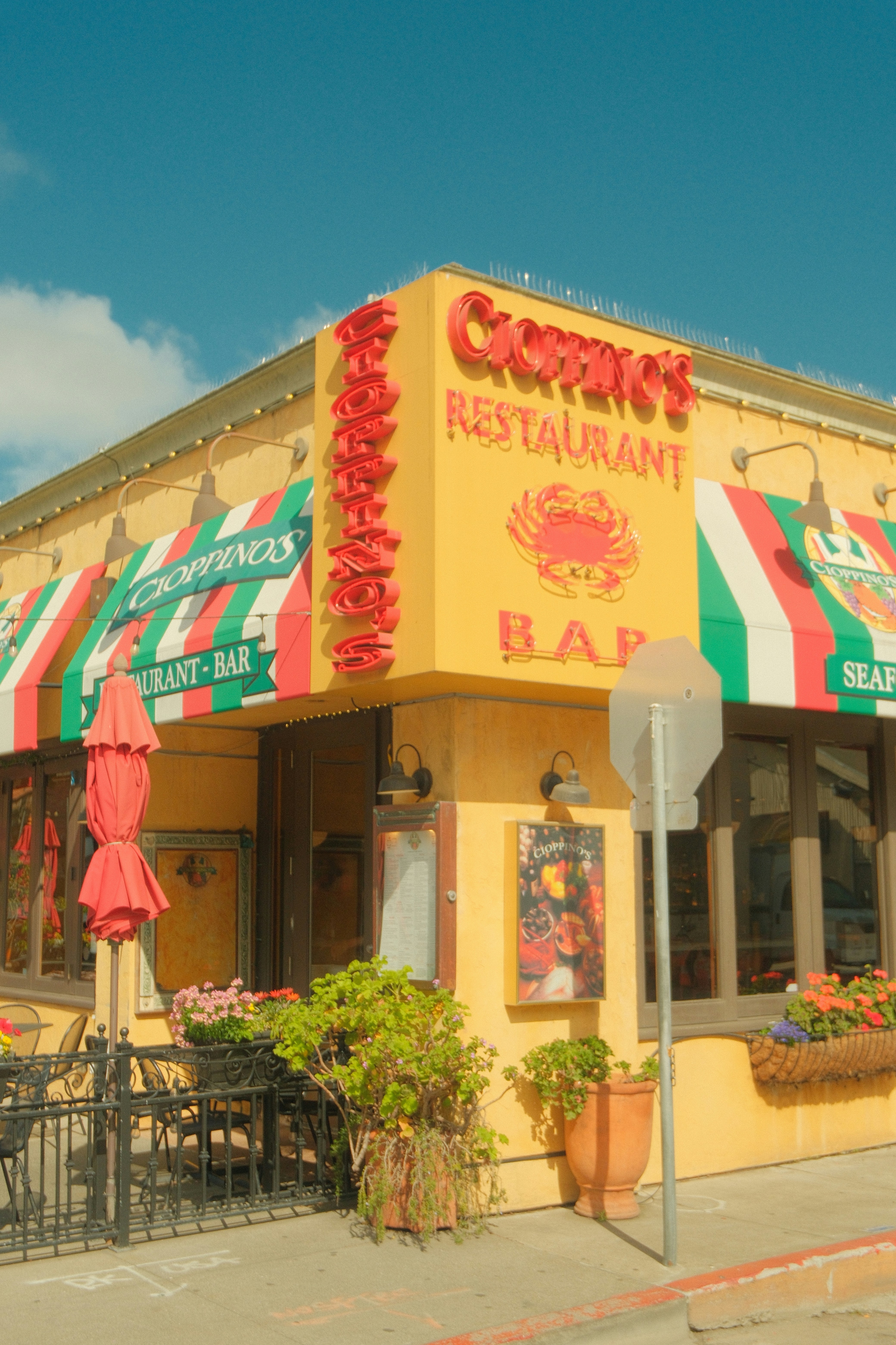 Sunny Corner Café: Colorful Mediterranean Facade and Striped Awnings