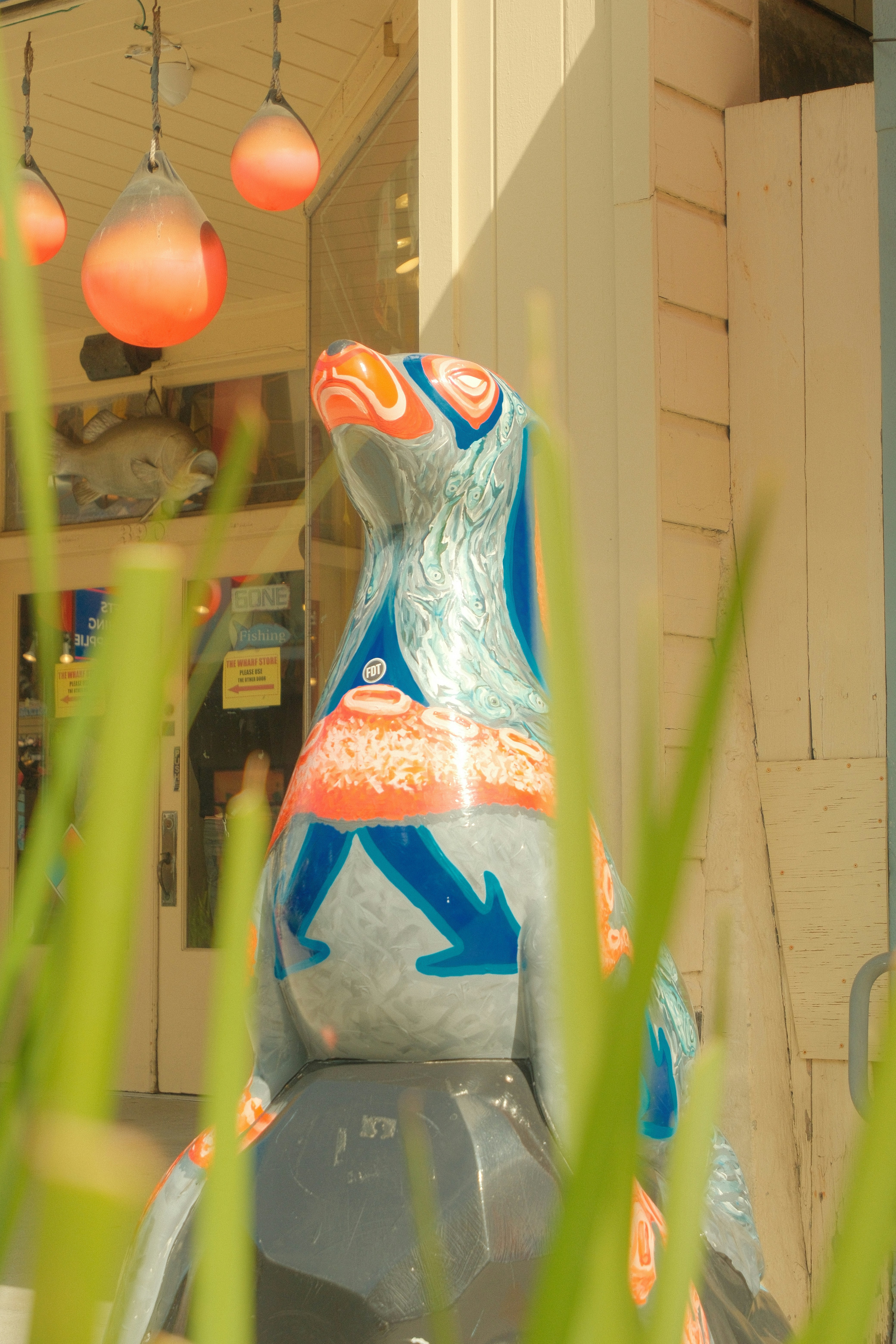 Colorful dinosaur sculpture framed by shop entrance and foreground blades