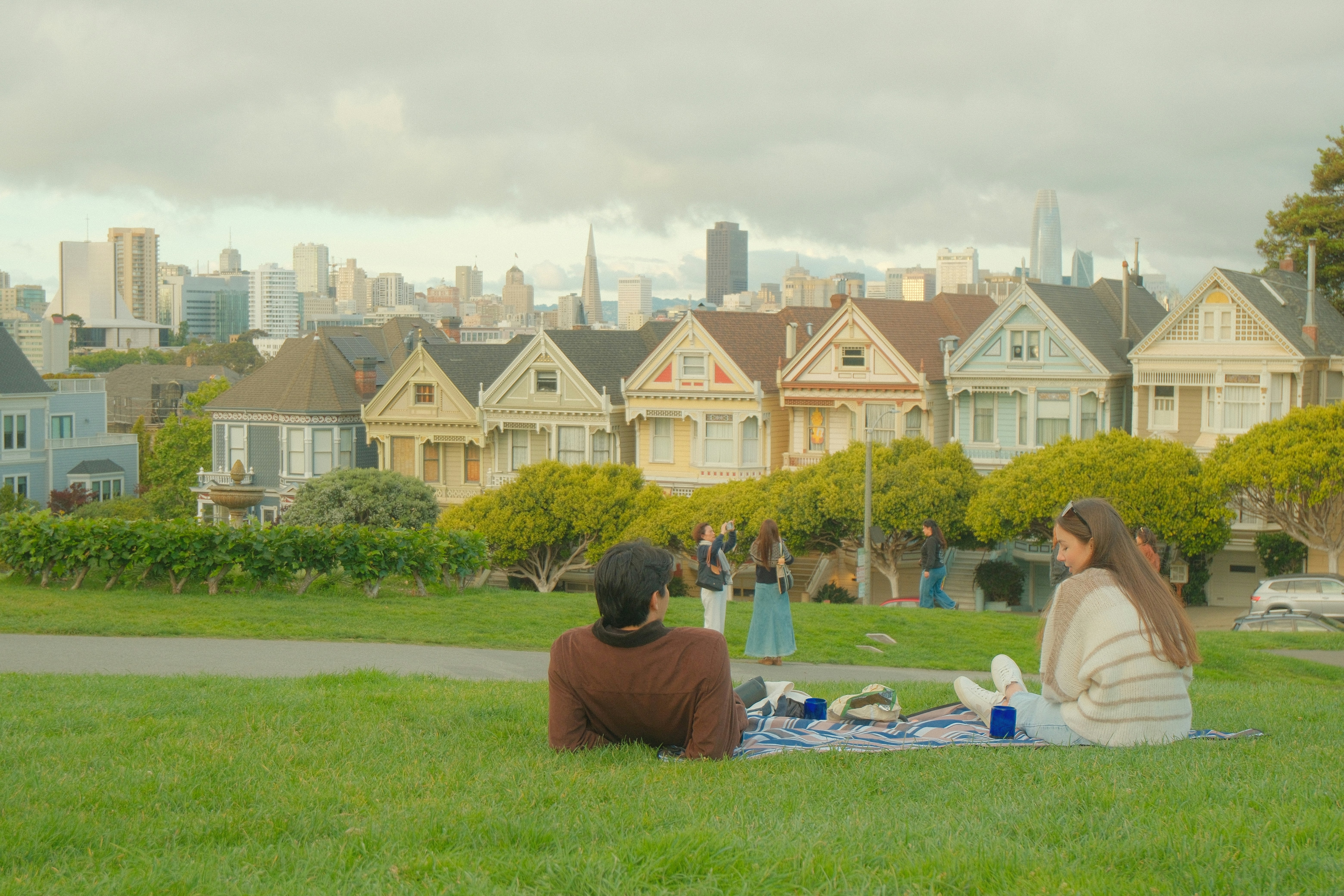 Picnic under pastel row of cottages with city skyline beyond