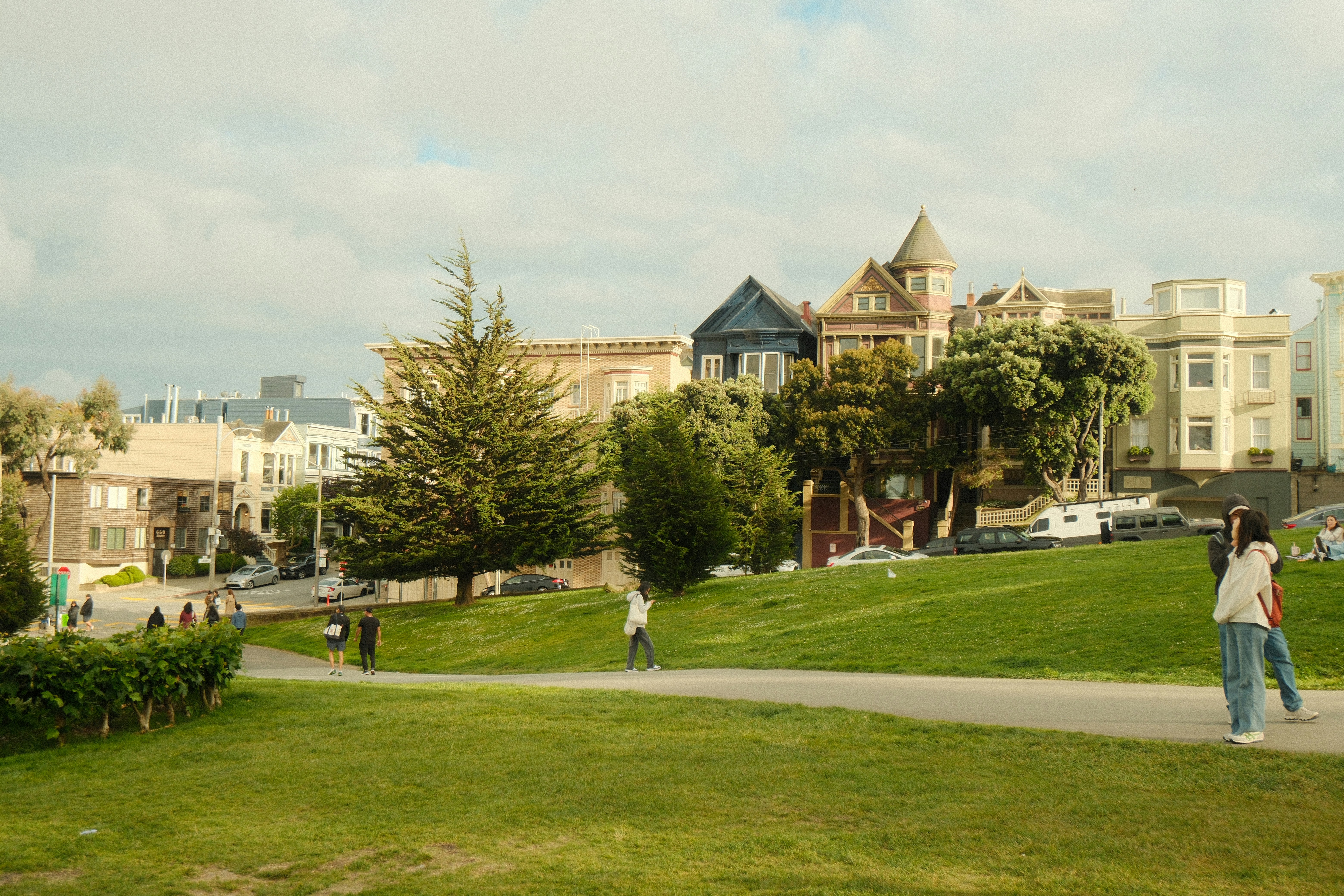 Sunlit Park Edge with Curious Figures and Row of Colorful Townhouses
