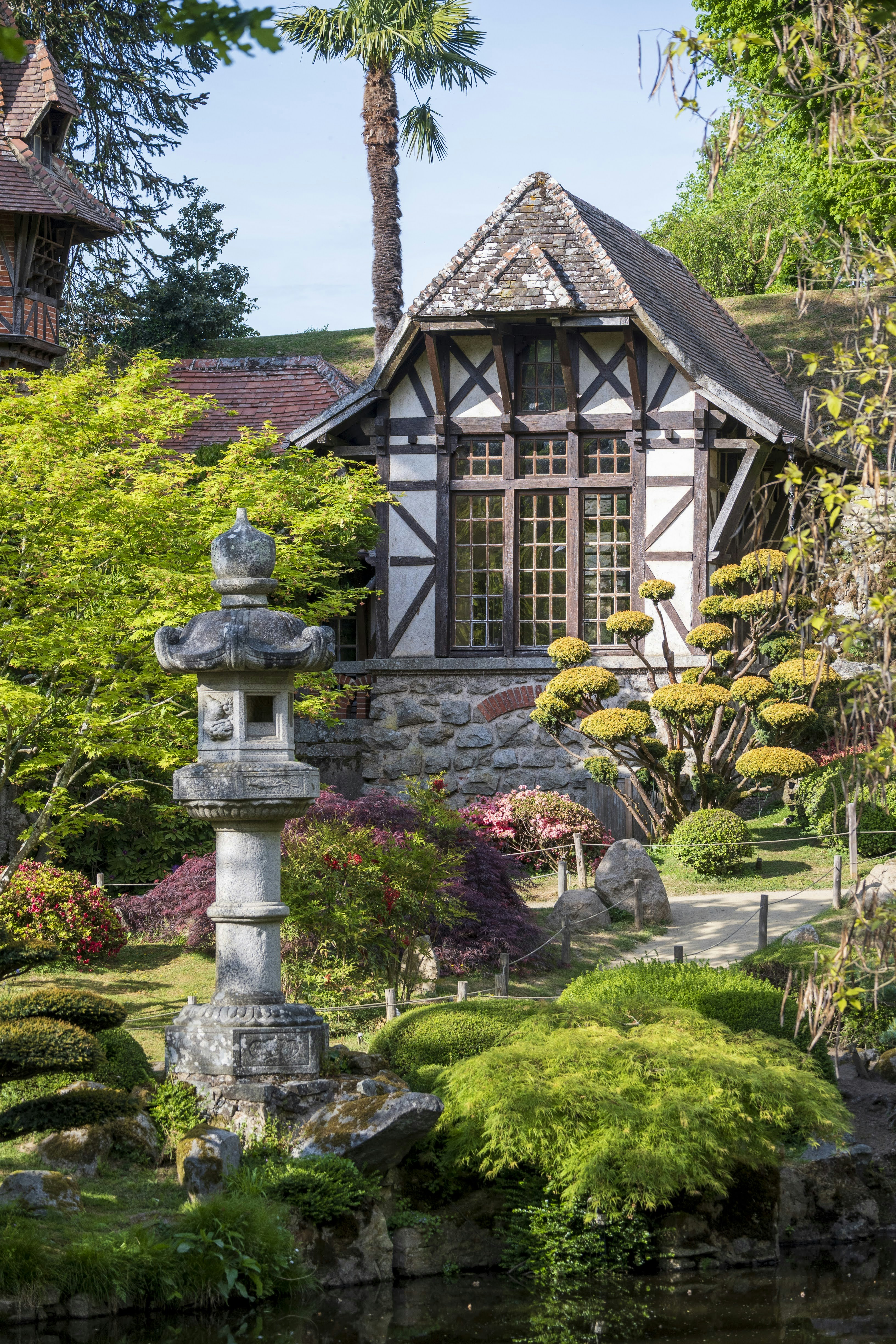 Quaint Tudor House Framed by Bonsai and Stone Lantern in Lush Japanese-inspired Garden