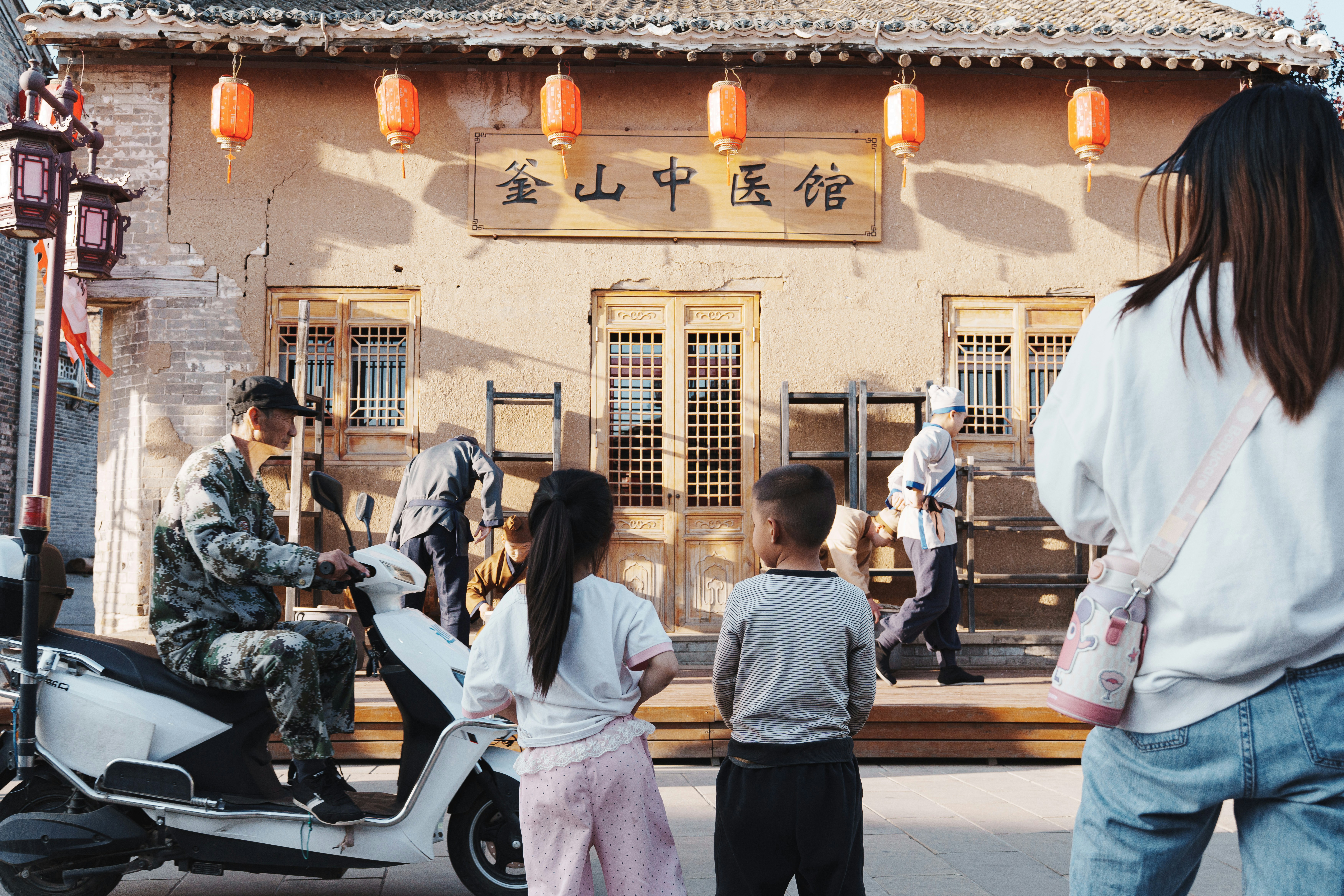 Courtyard Circles: Families Crouched by the Traditional Facade