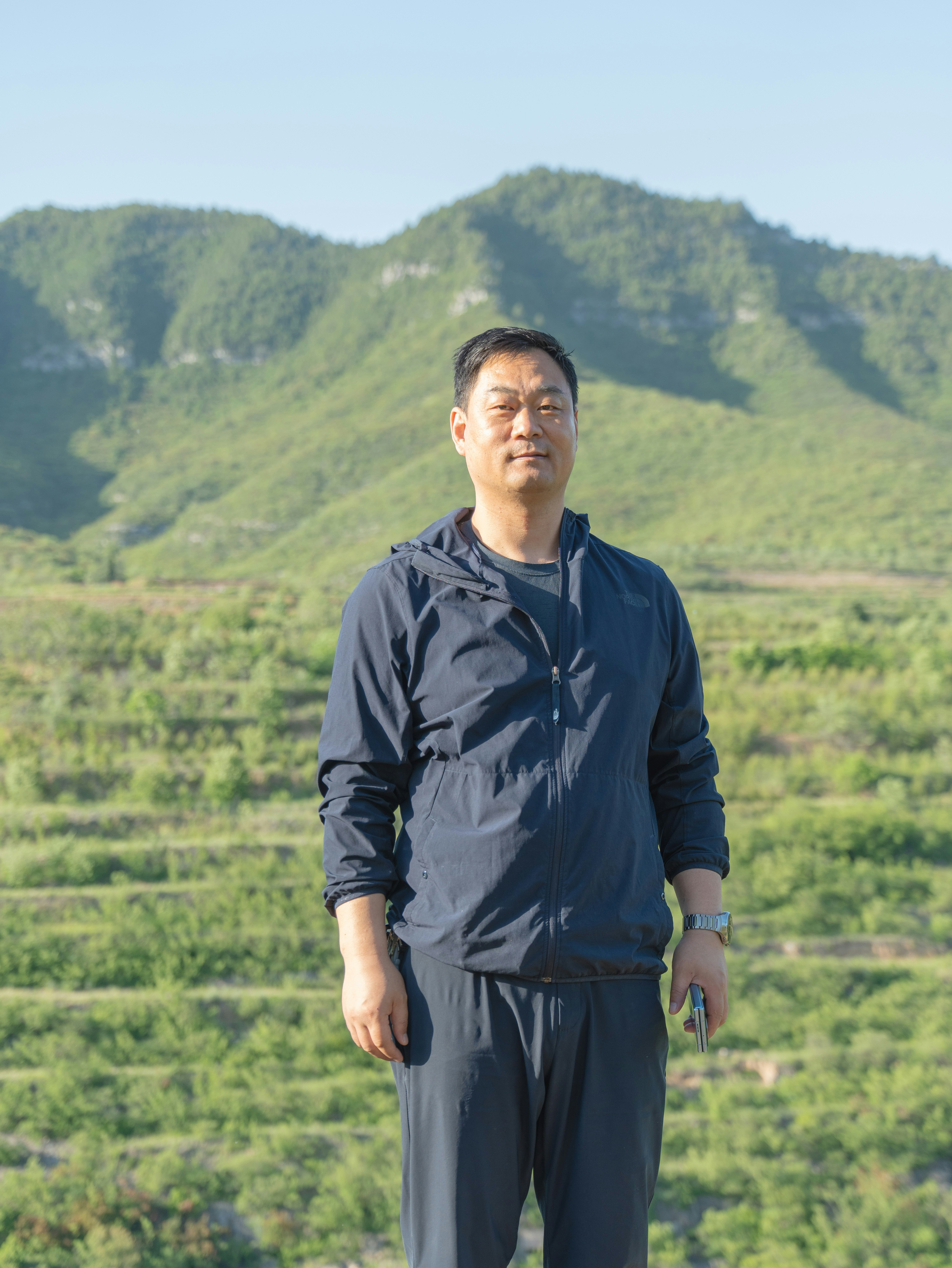 Serene Overlook: A man in a navy windbreaker against terraced hills