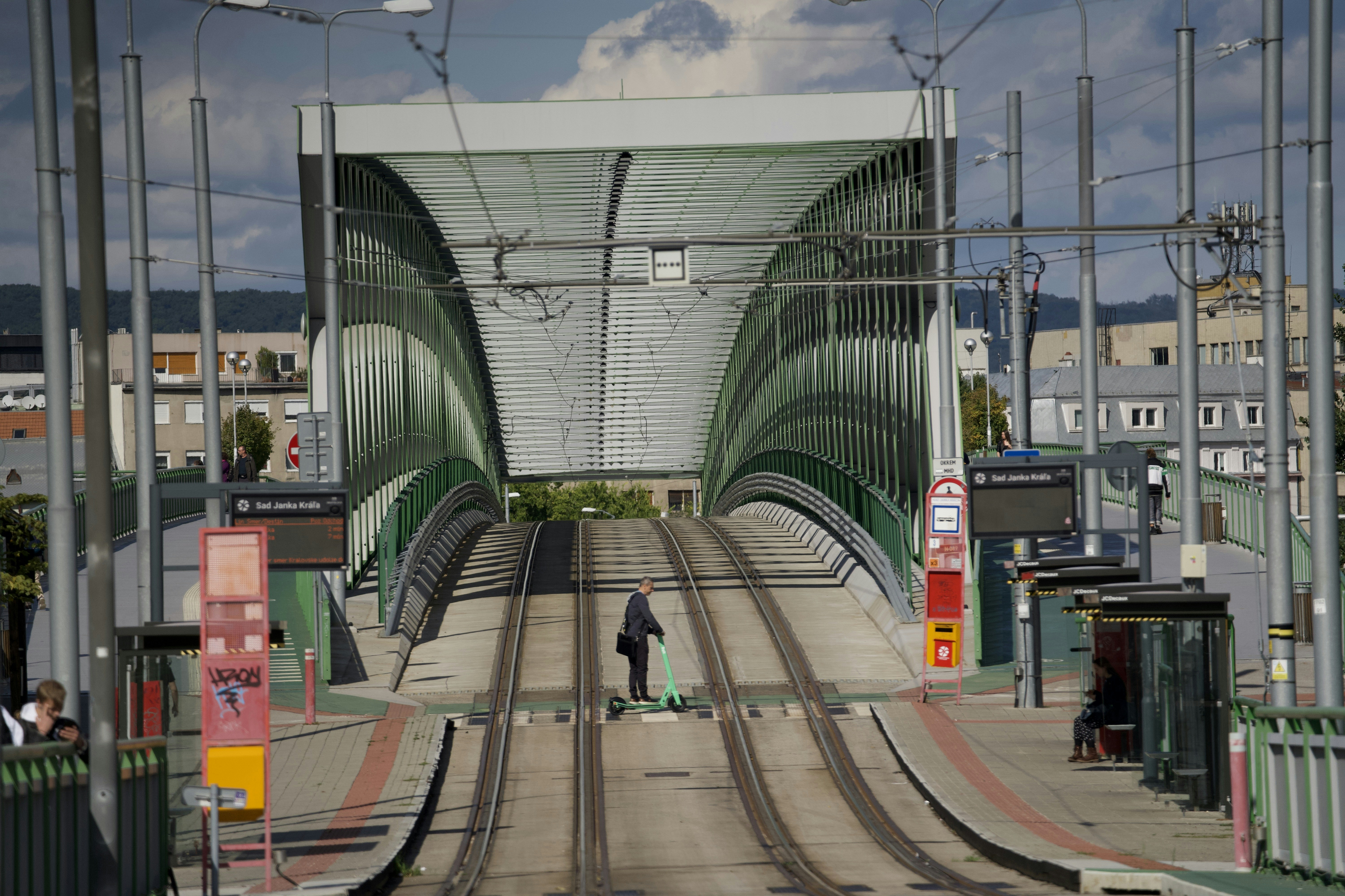 Pedestrian on a Green Arched Railway Bridge Opens a Quiet Path Across Tracks