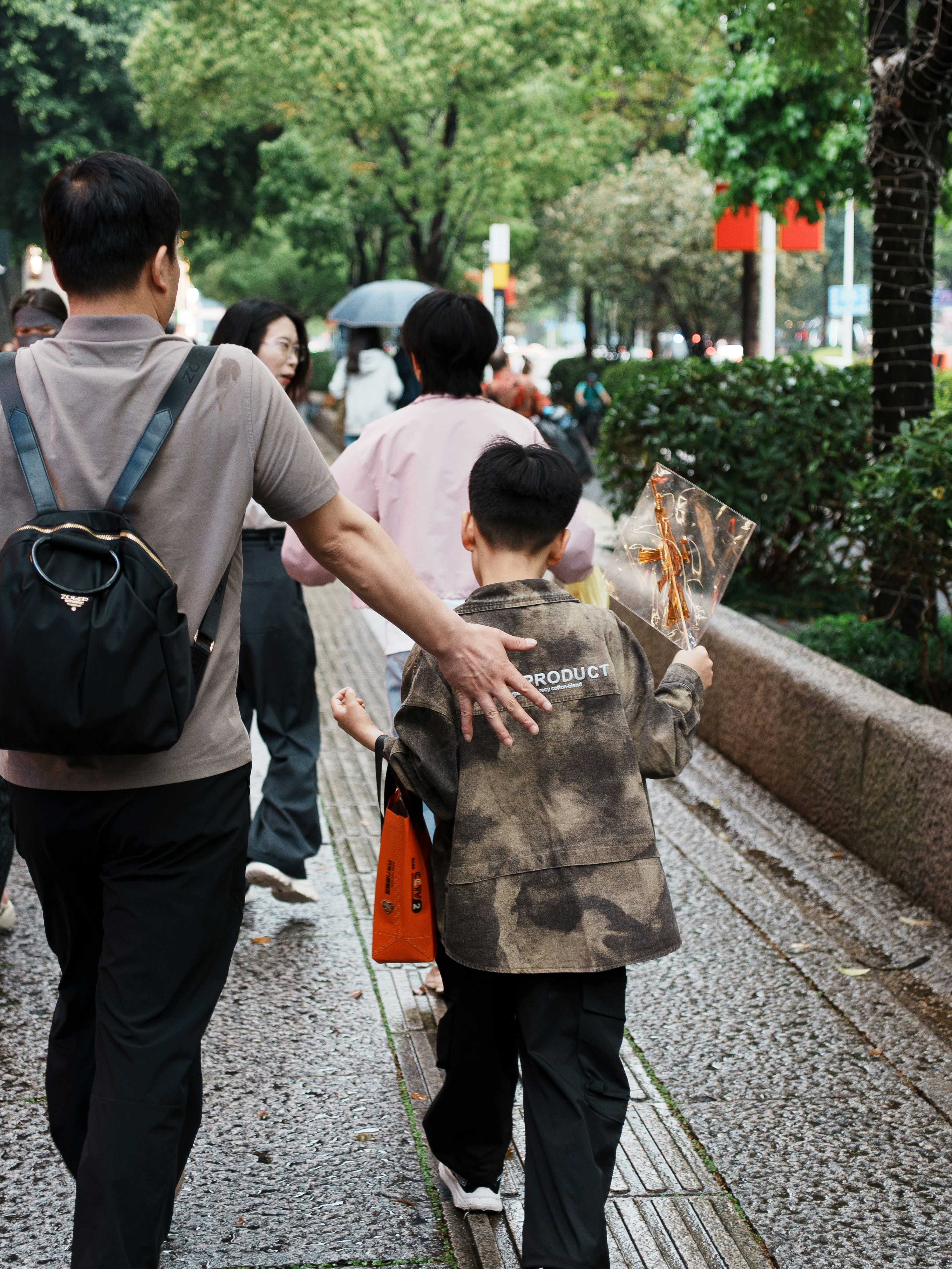 Father Guides Child Through a Bustling Outdoor Path