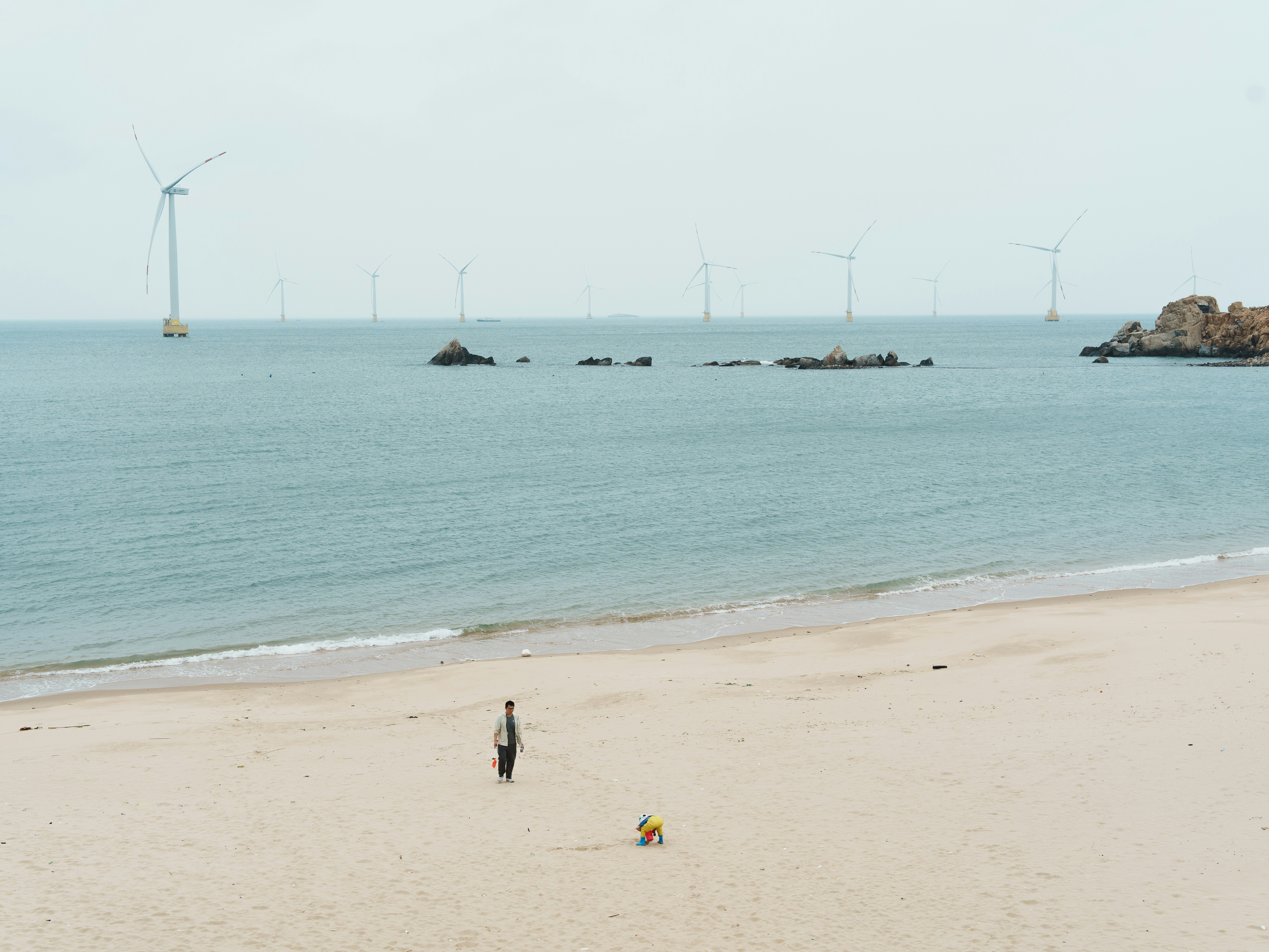 Lonely Beachwalker Beneath Distant Wind Farms
