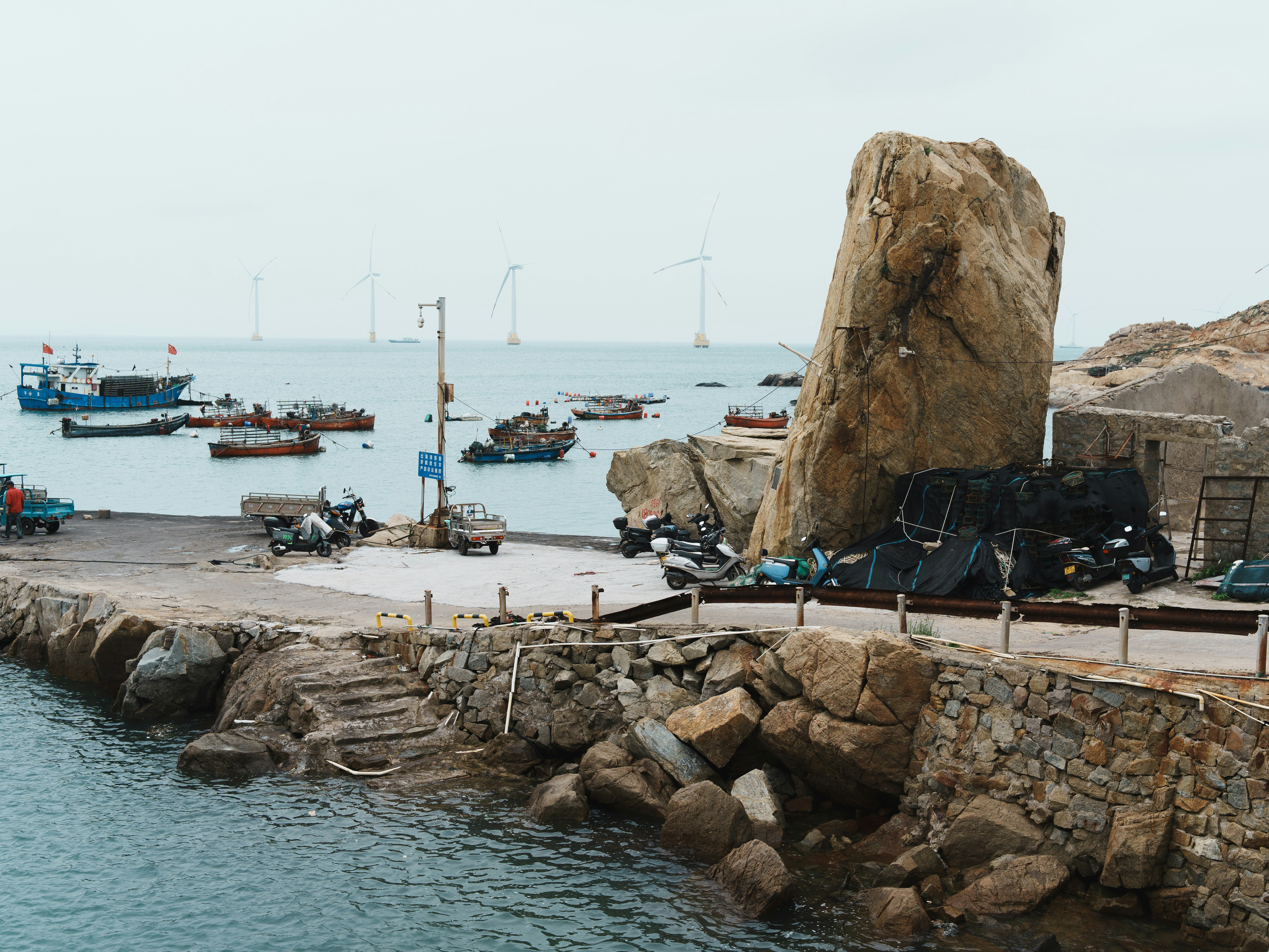 Harbor Ruggedness: Boats at Rest by a Weathered Breakwater
