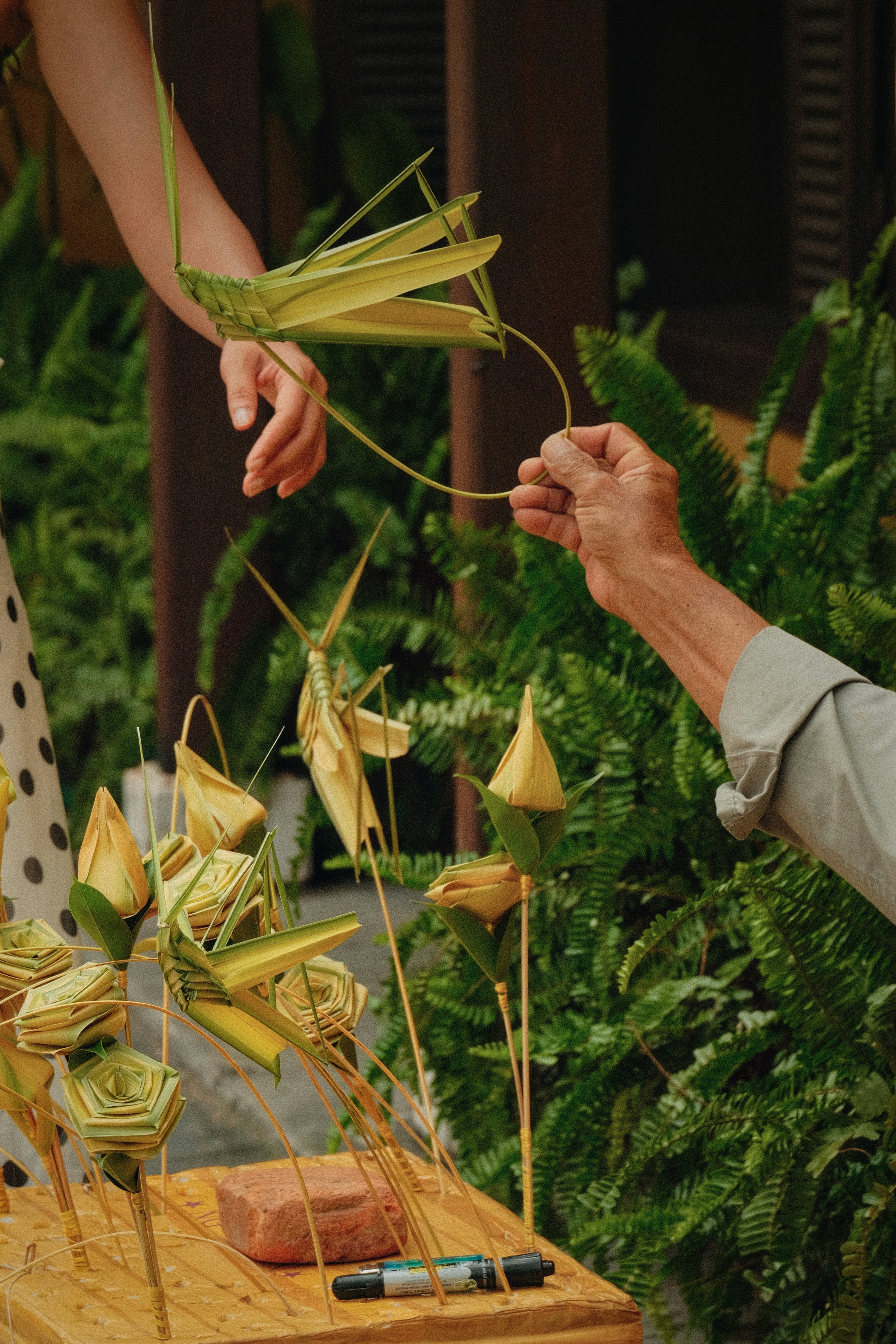 Hands of Tradition: Crafting the Leafy Crown over a Wooden Table
