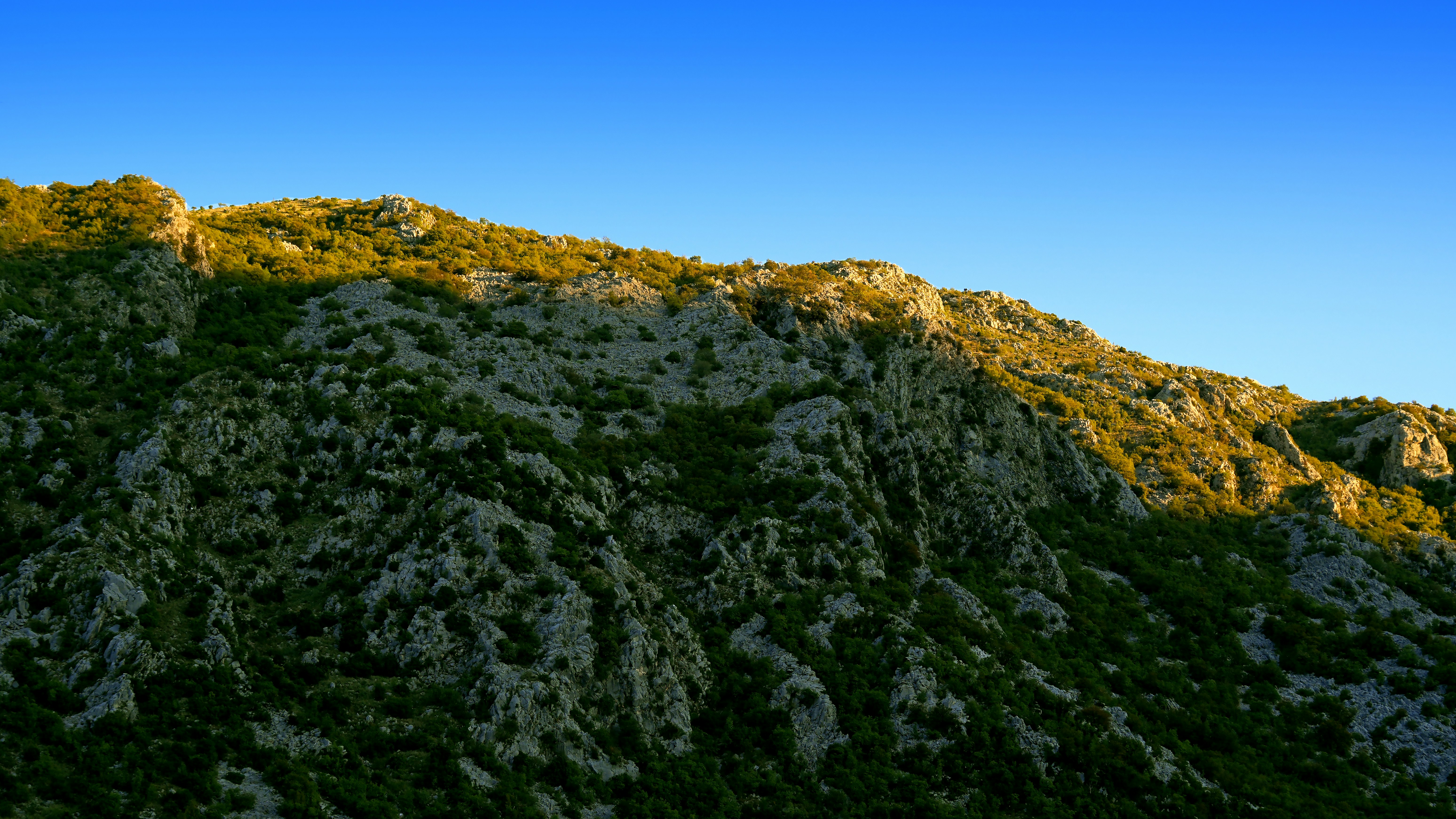 Golden Ridge at Dusk: A Sunlit Crest Over Rugged Terrain