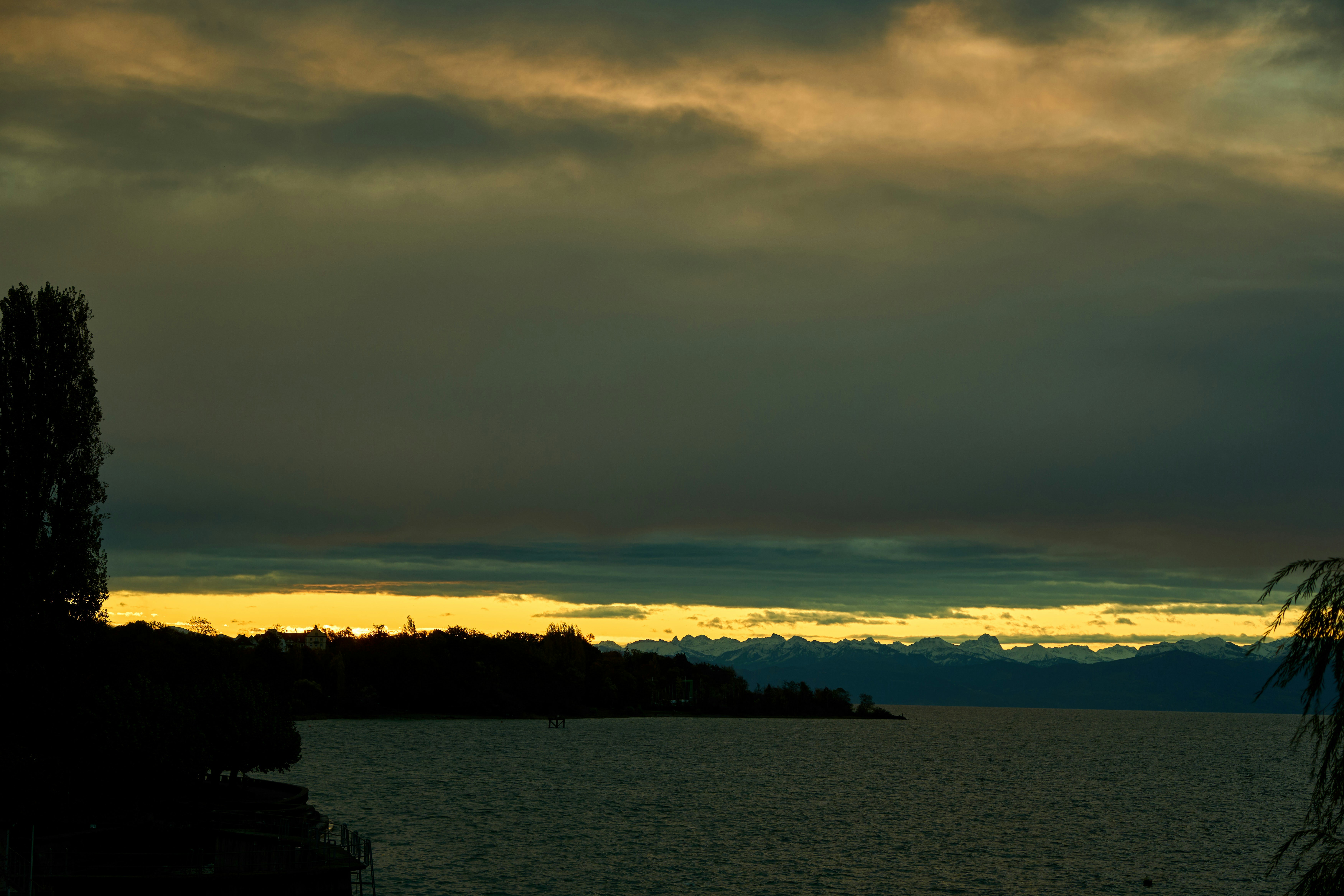 Dawn on the Quiet Lake: Horizon Glow Over Silhouetted Shore