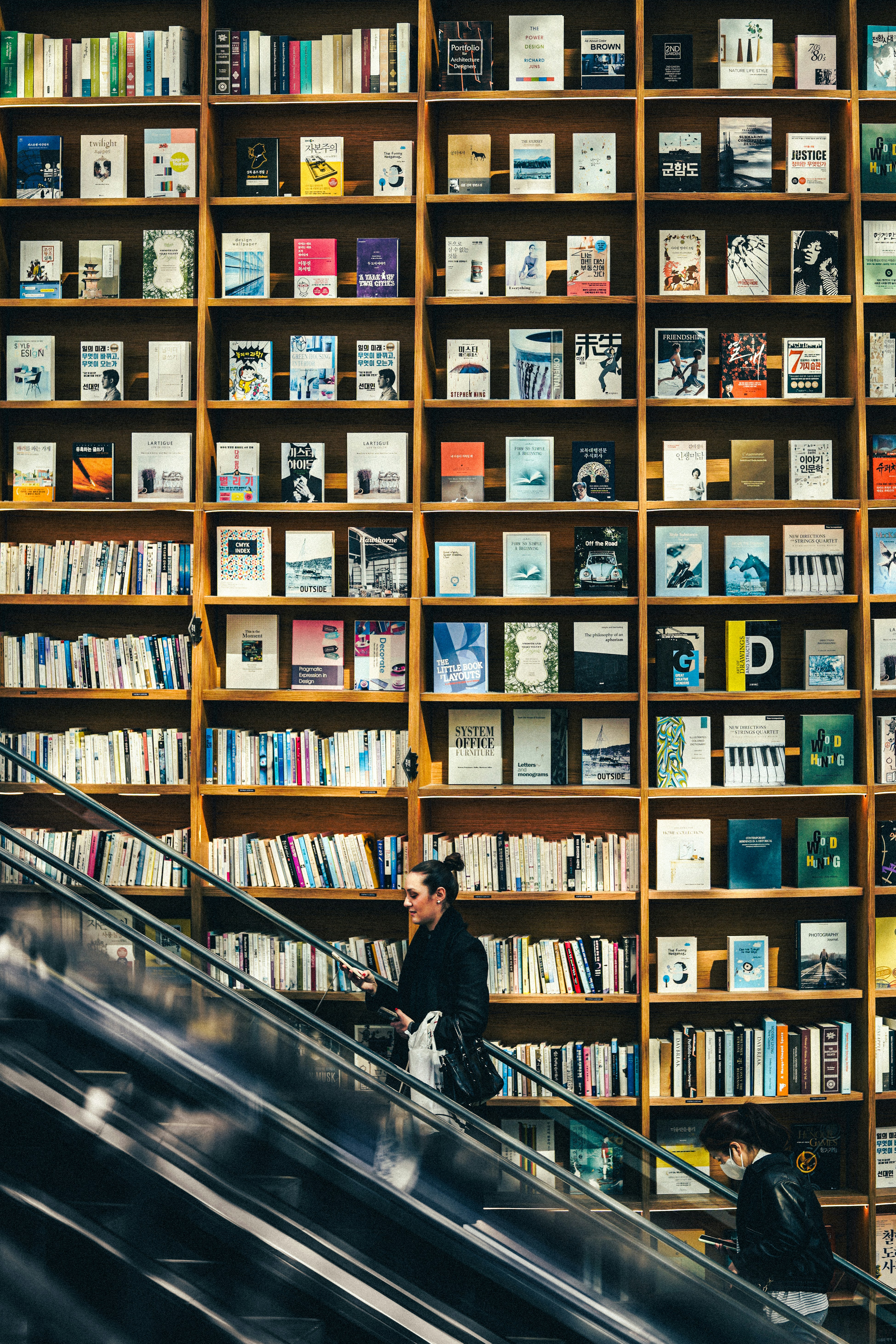 Library in Motion: A Ascending View of a Bookshelf via Escalator Ride