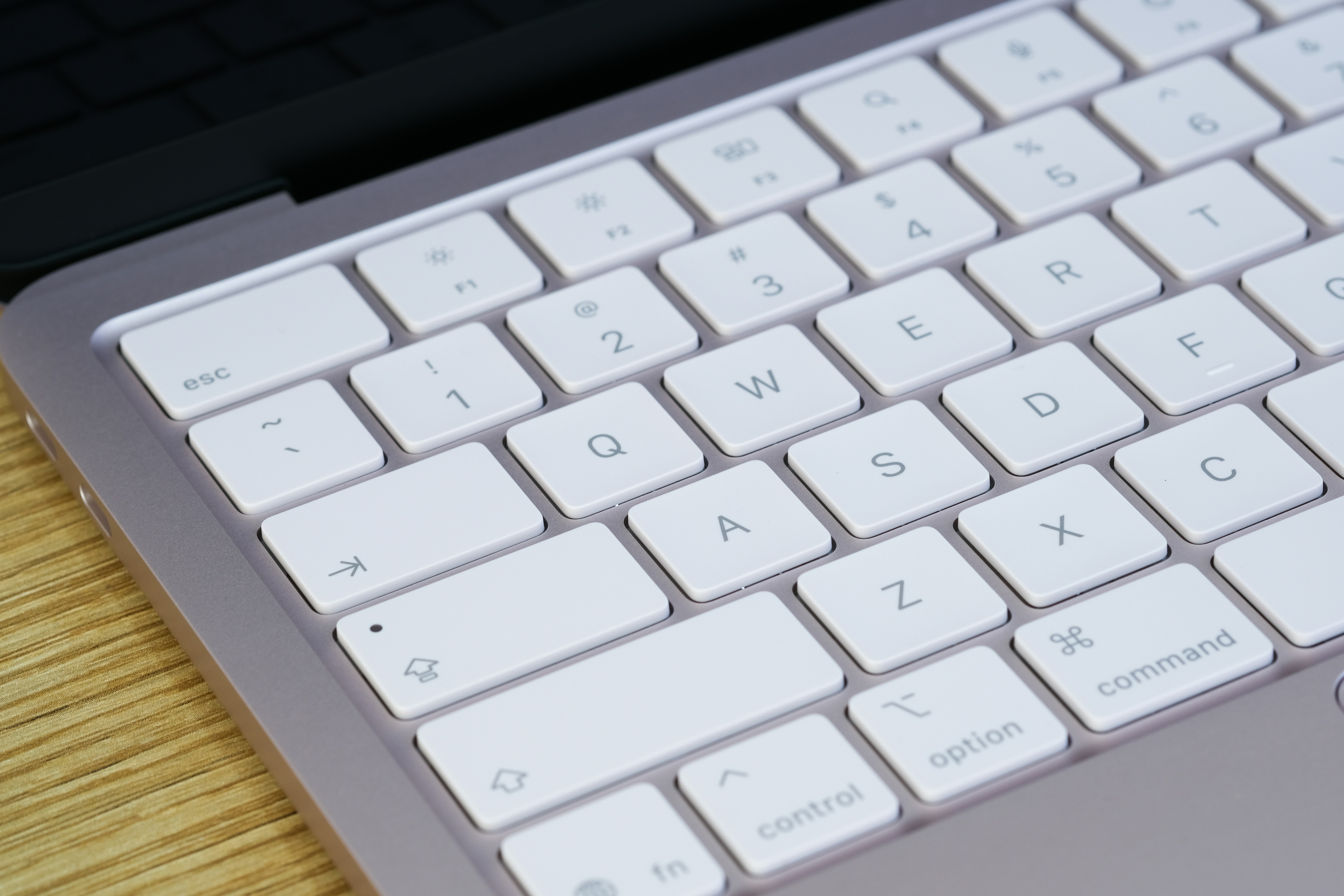 Close-up on a laptop keyboard: glossy keys and soft wood surface
