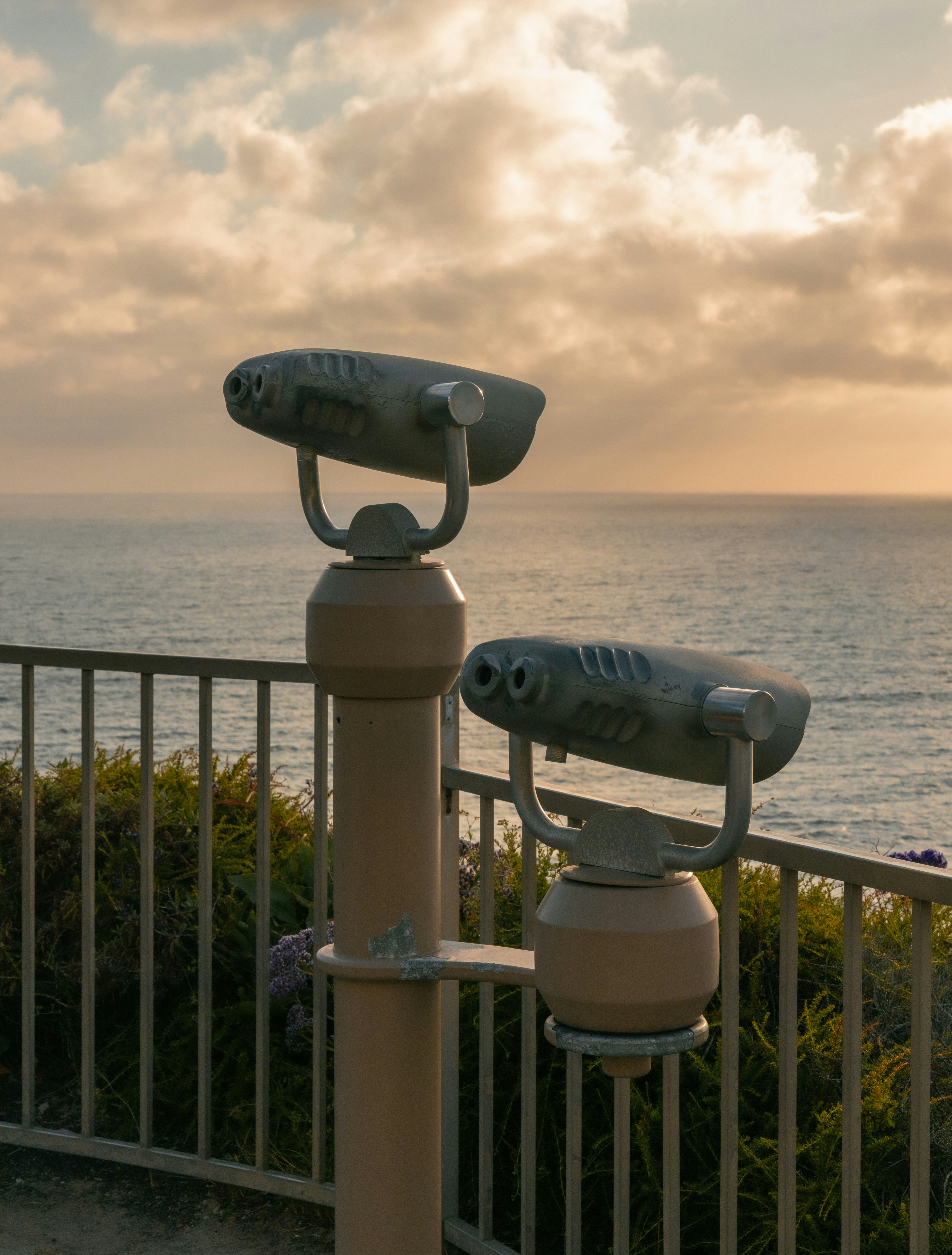 Twin sea-scope gazers at sunset overlook