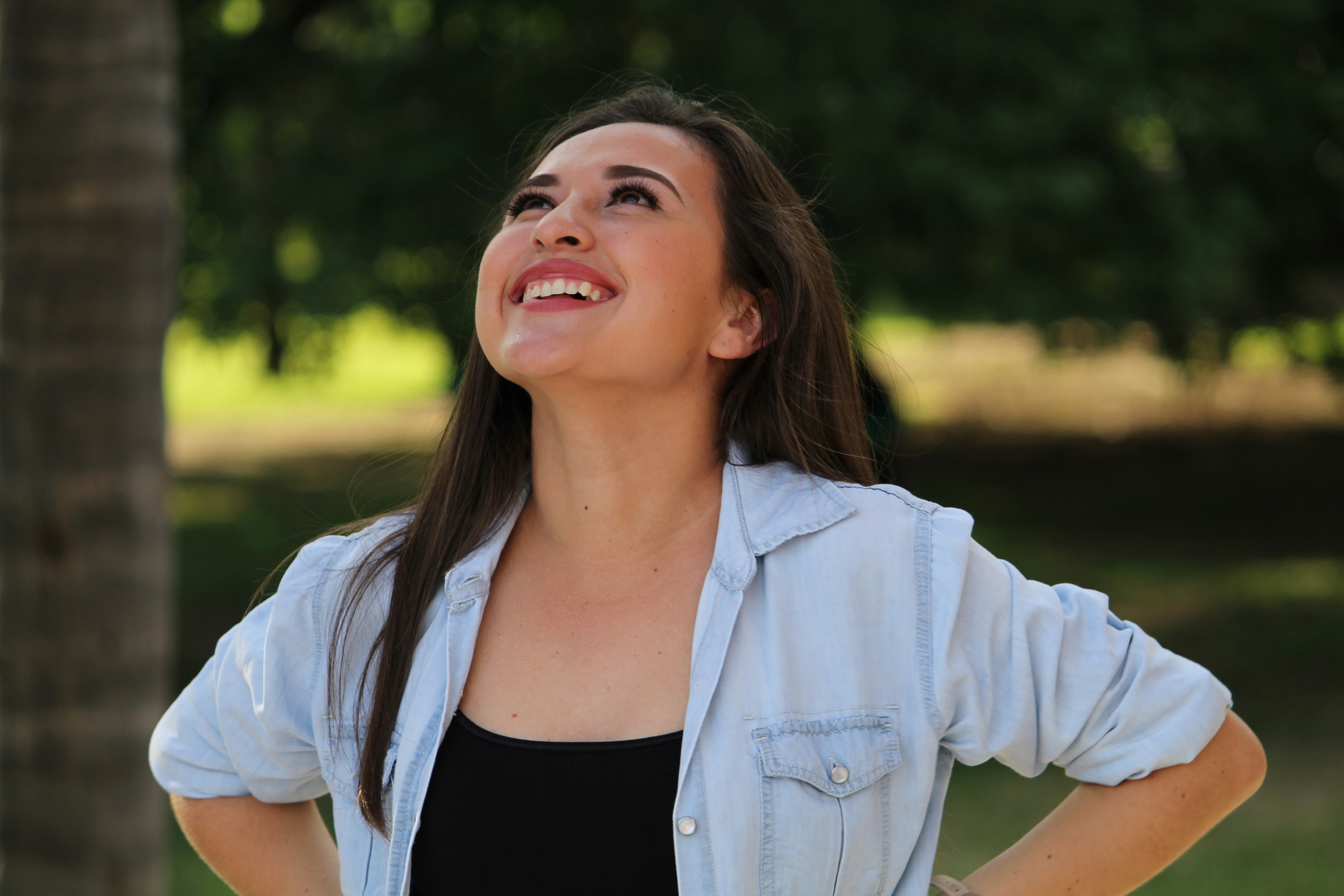 Sunlit Confidence: A Woman Grinning Upward Under Open Sky