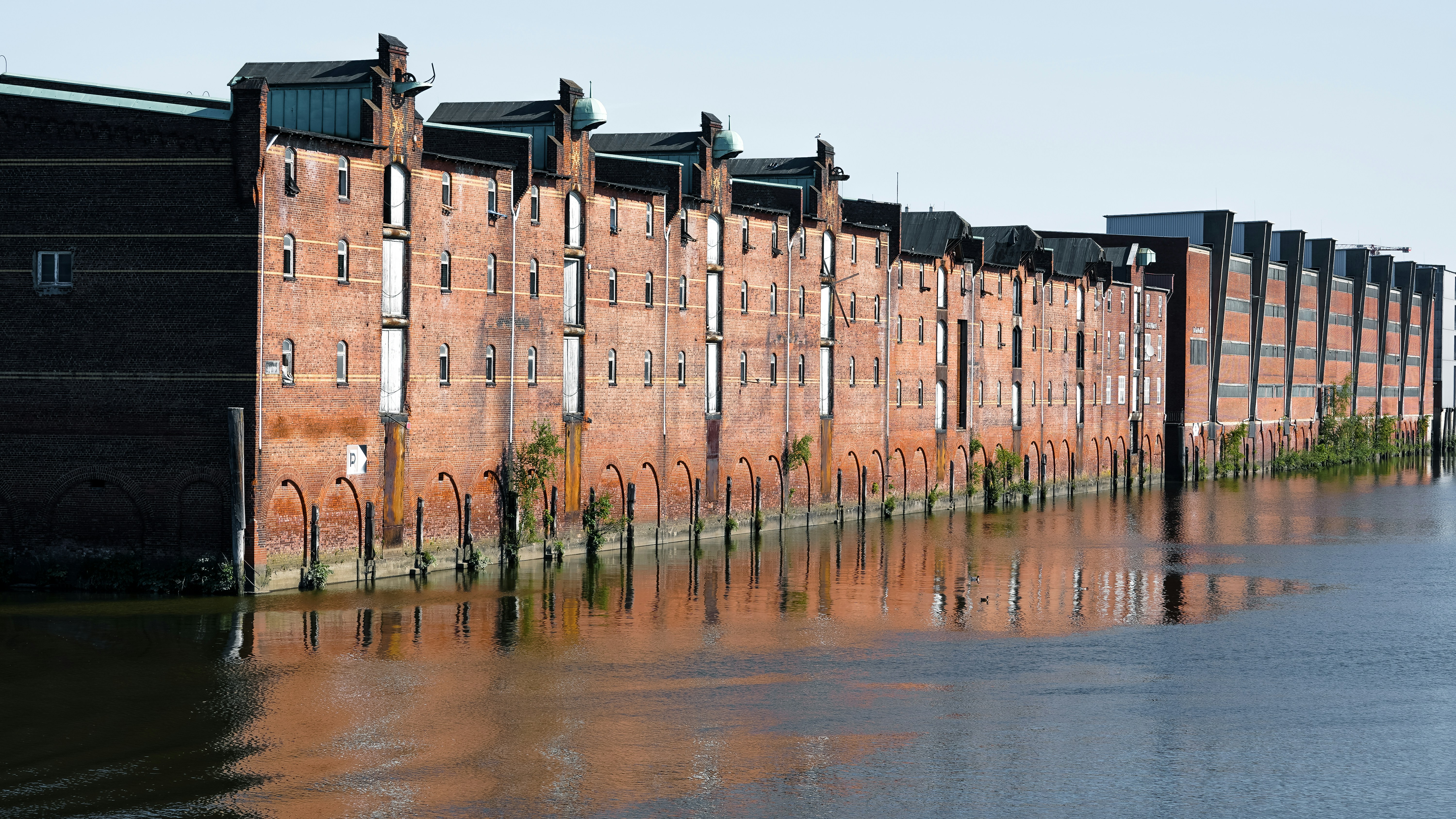 Brick riverside mill: reflections and range of windows along a calm waterline