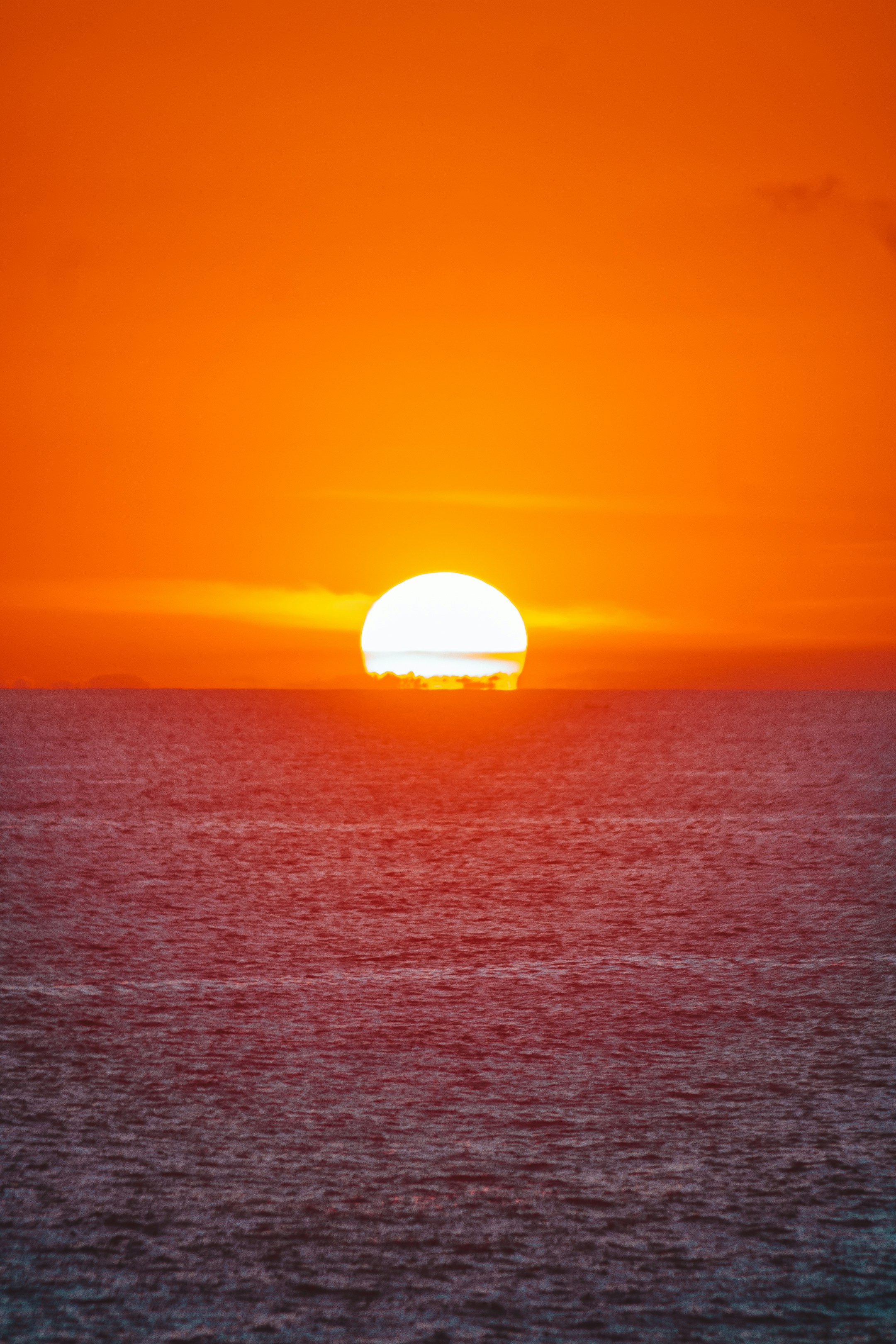 Sunkissed Horizon: The Sun Dips Behind a Quiet Sea