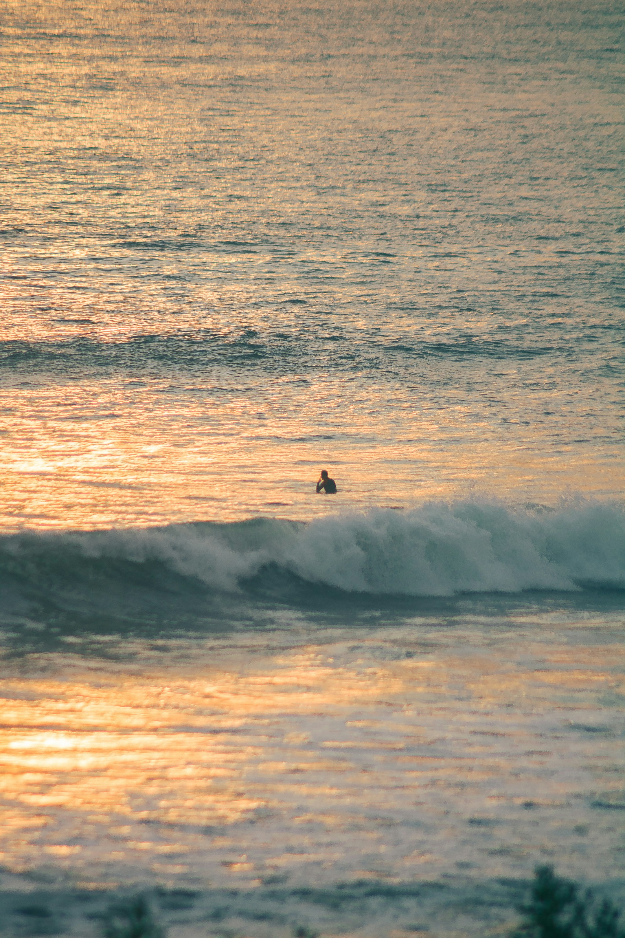 Solitary Surfer at Sunset: A Quiet Moment Amid Gentle Backwash