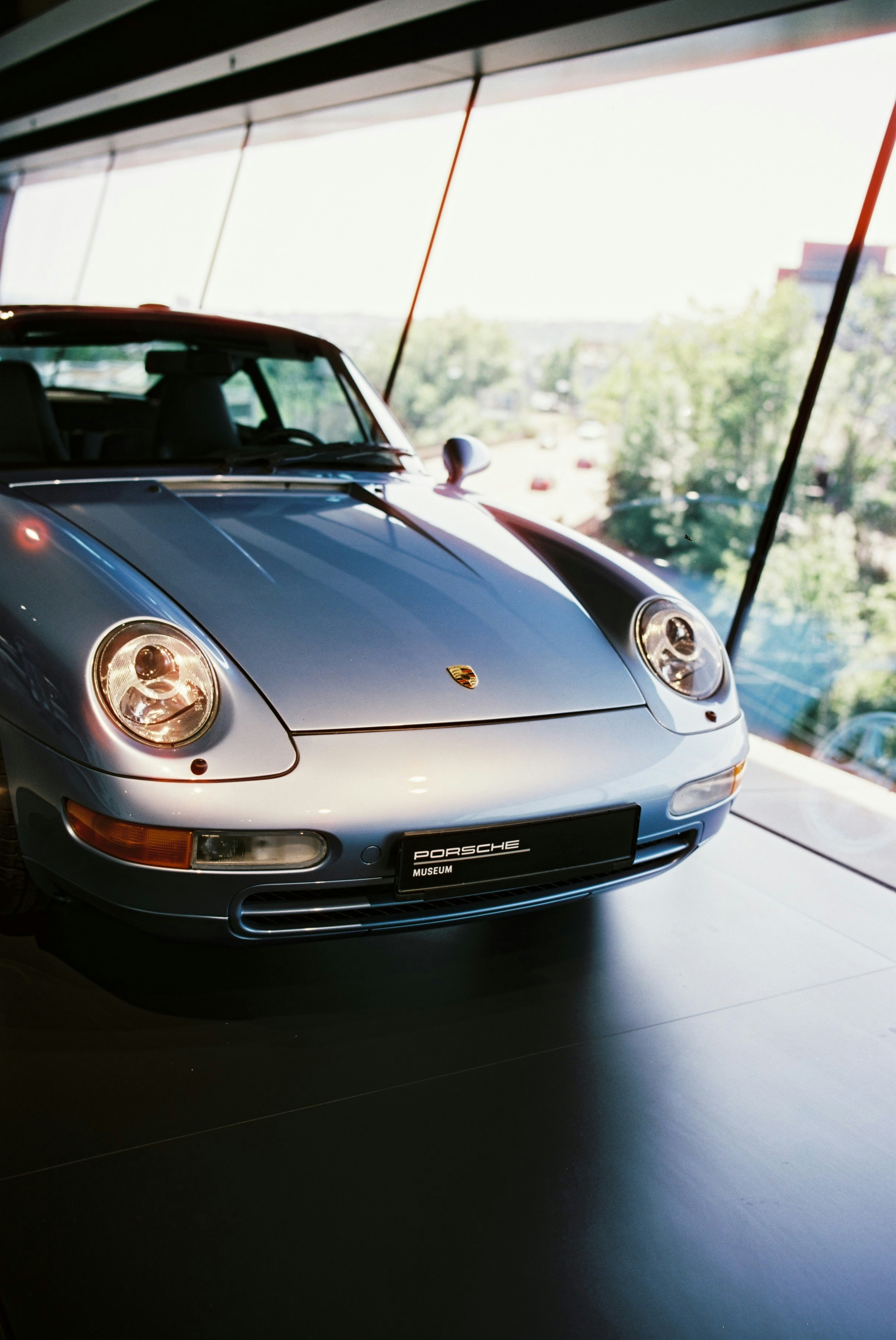 Porsche in a Glassy Showcase: A Classic Silver Curve Within Modern Light