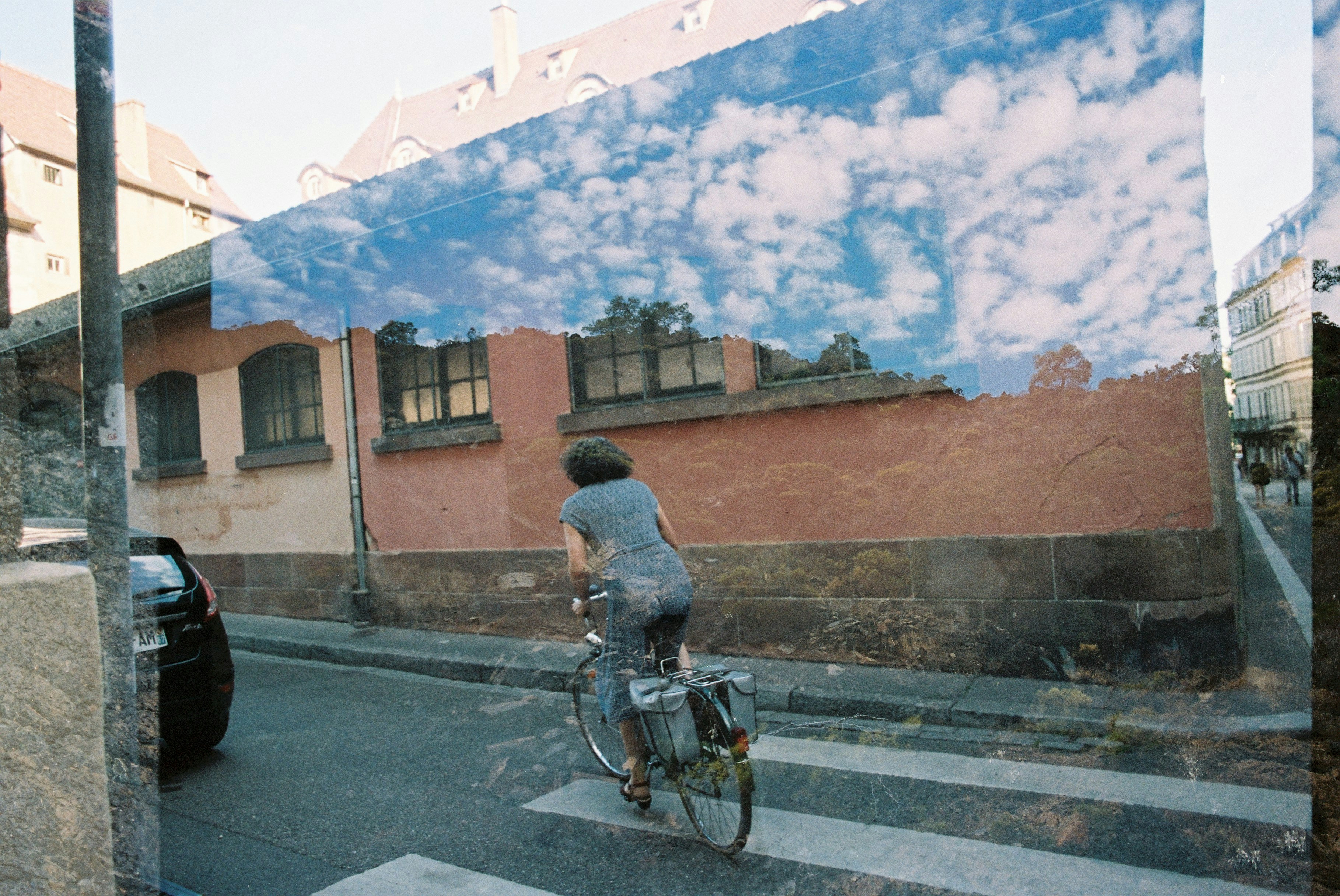 Cyclist Crossing a Quiet Urban Street Reflected in Glass