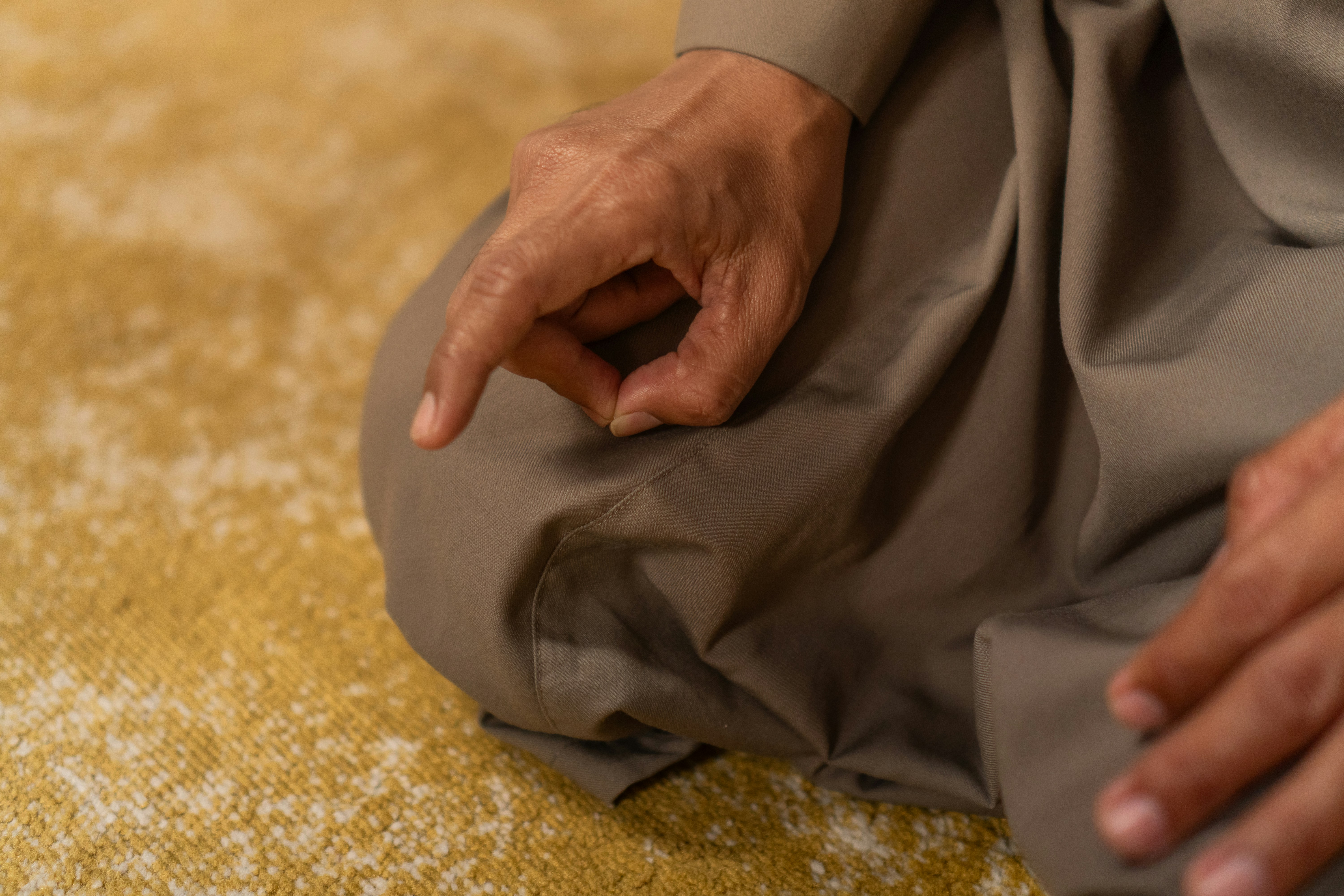 Hands at Rest: A Quiet Moment on a Textured Golden Rug