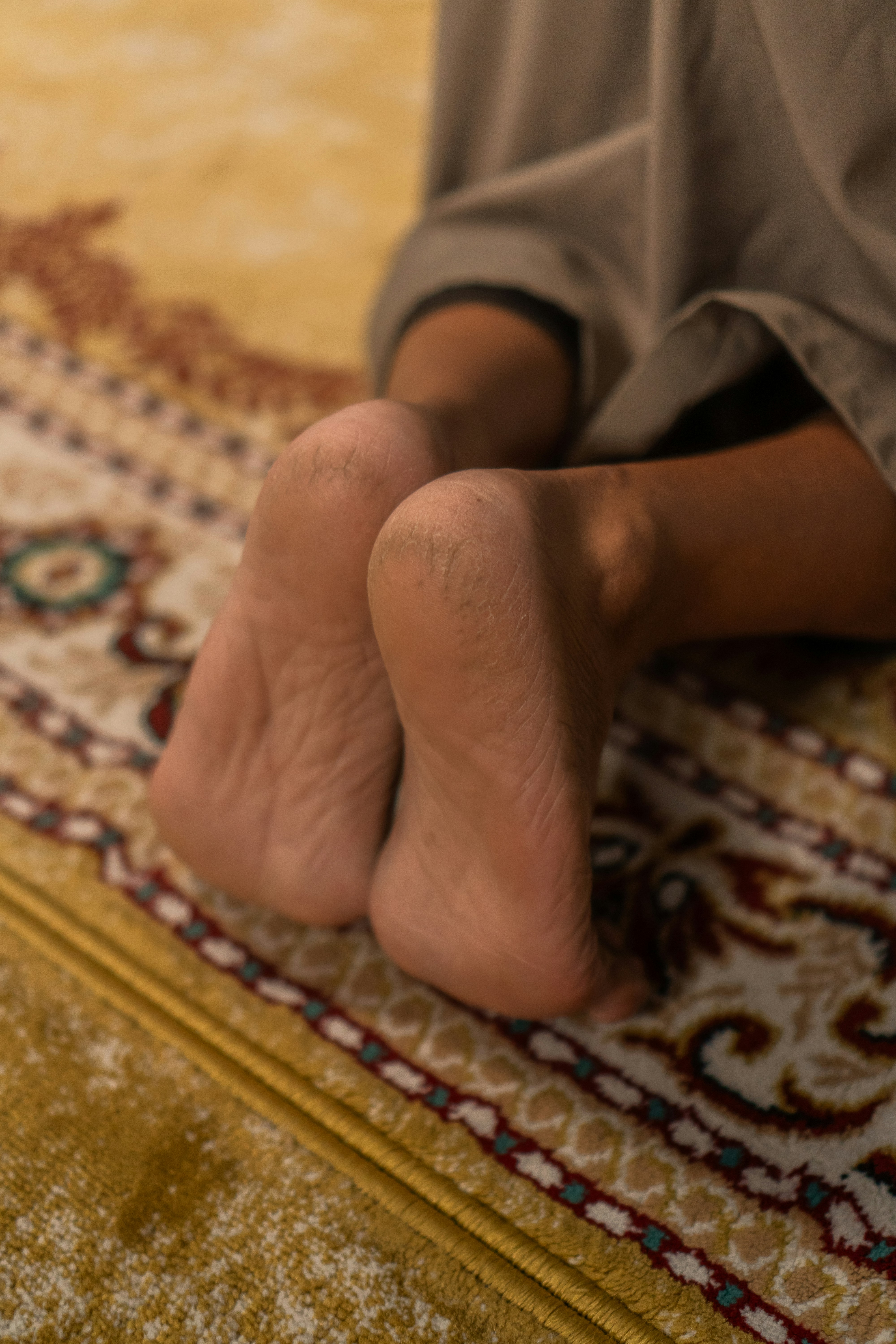 Bare soles on a patterned rug: a quiet resting moment
