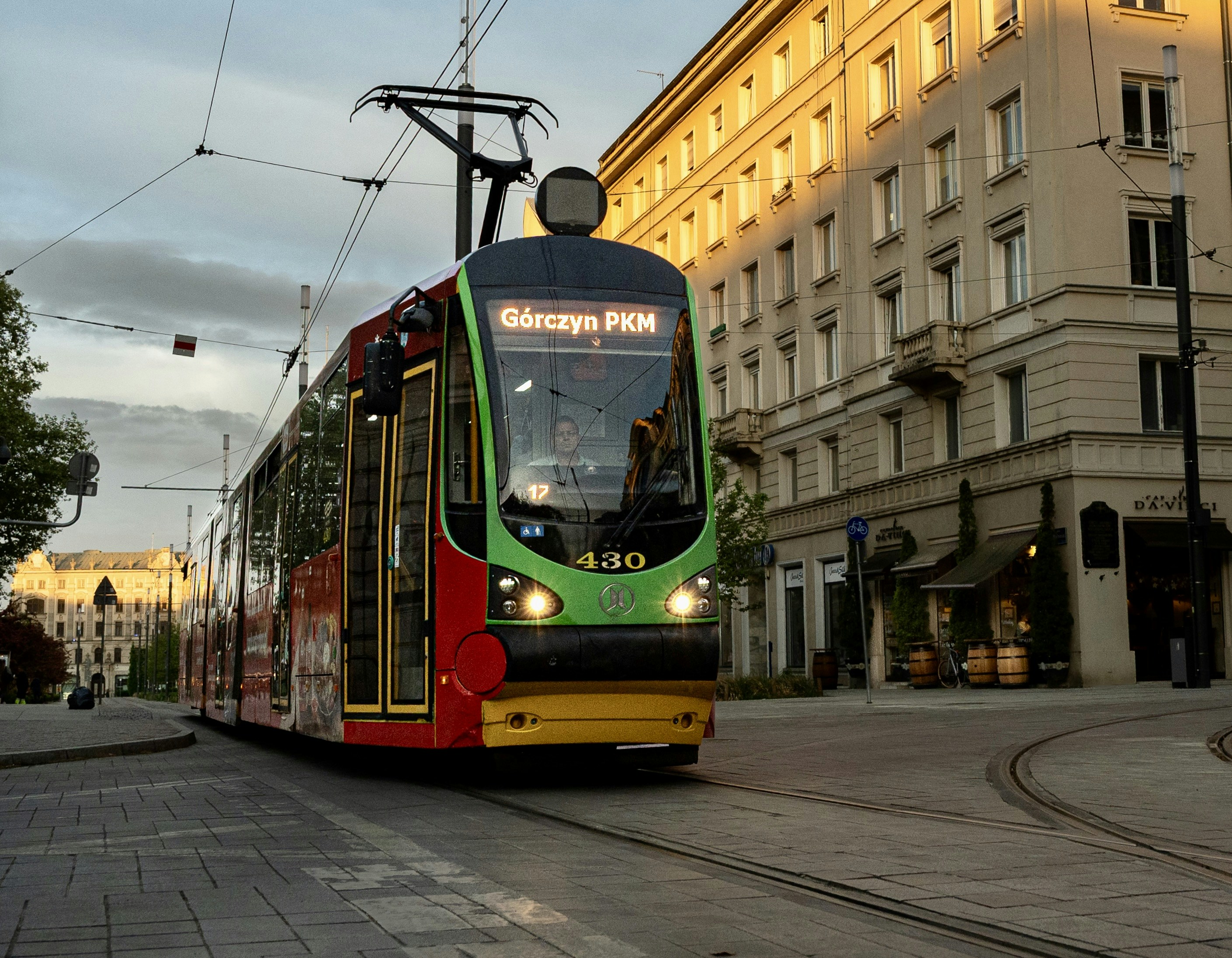 Emerald tram gliding through a sunlit city street