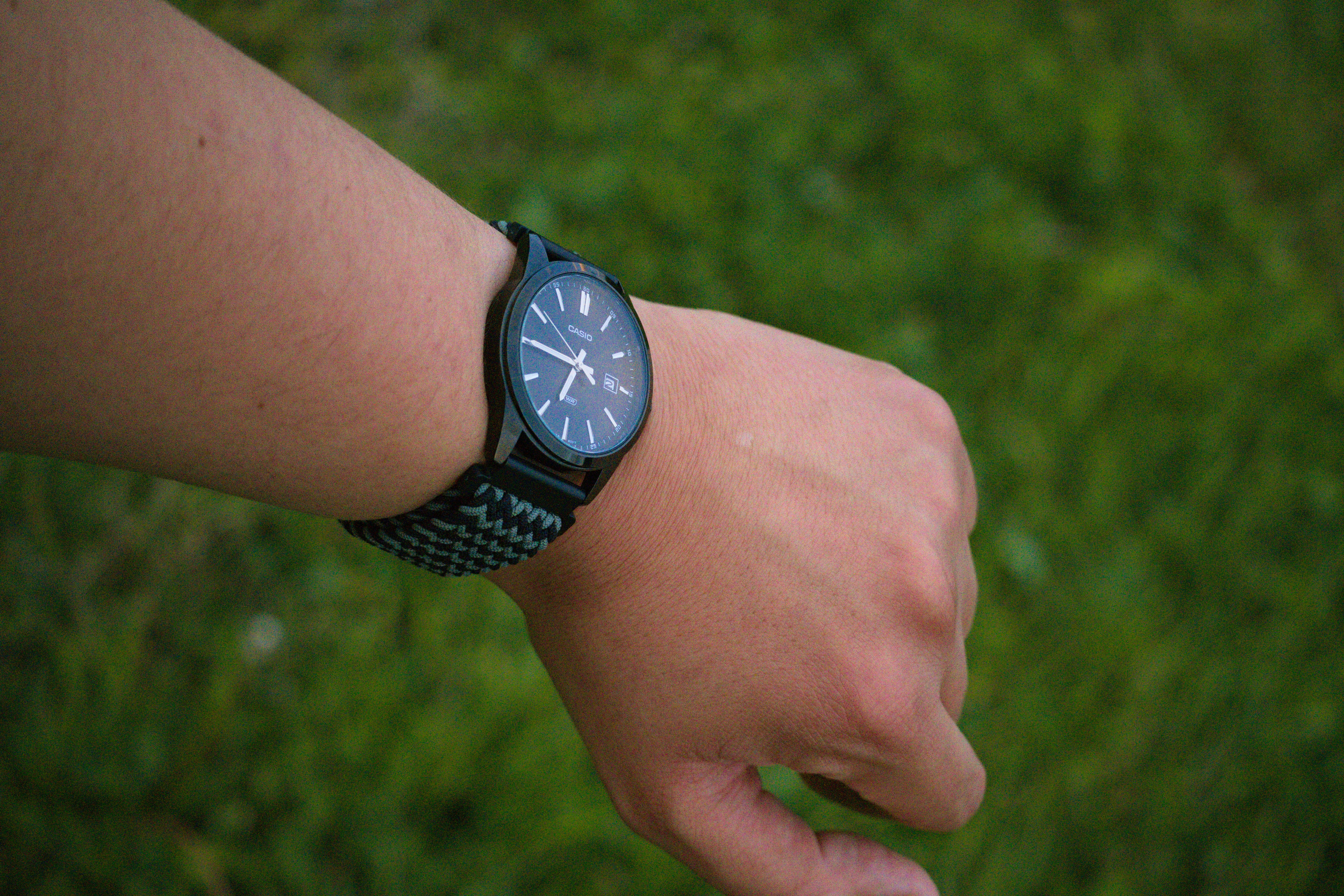Minimalist wristwatch in motion on a green lawn