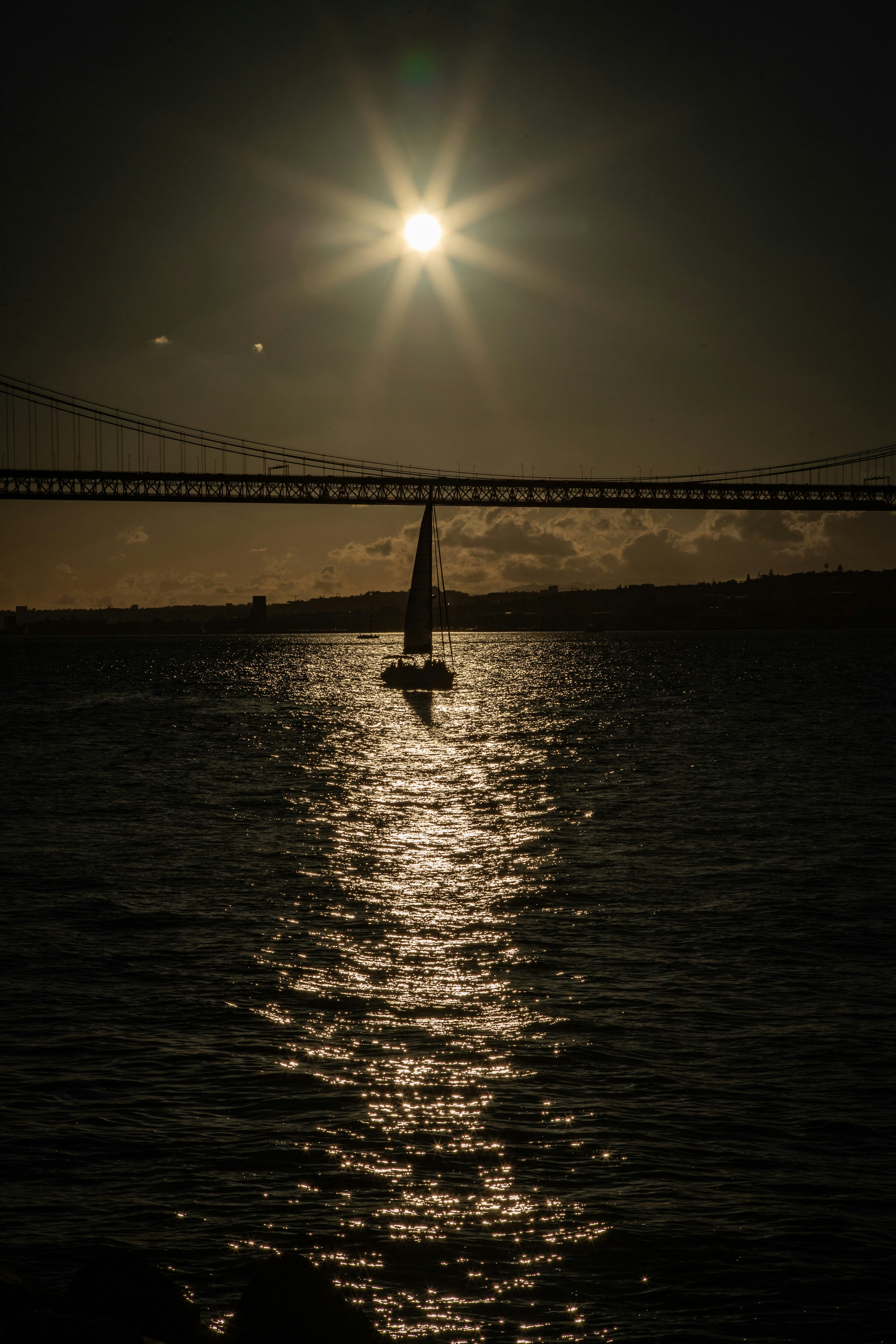 Silhouette and Sail: Sunset over the River with a Glassy Path of Light