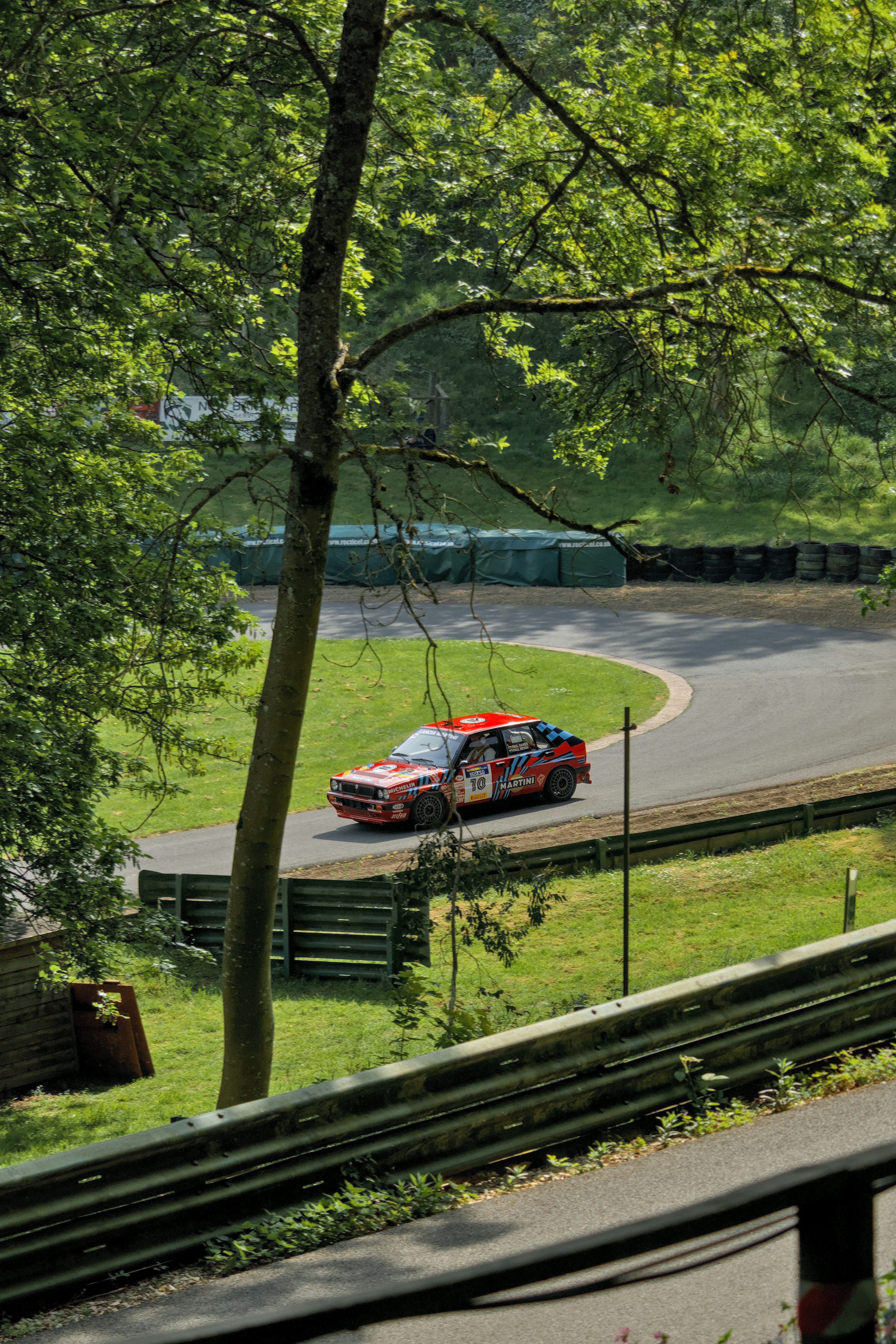 Red Rally Car Rounds a Curve Through a Lush Forest