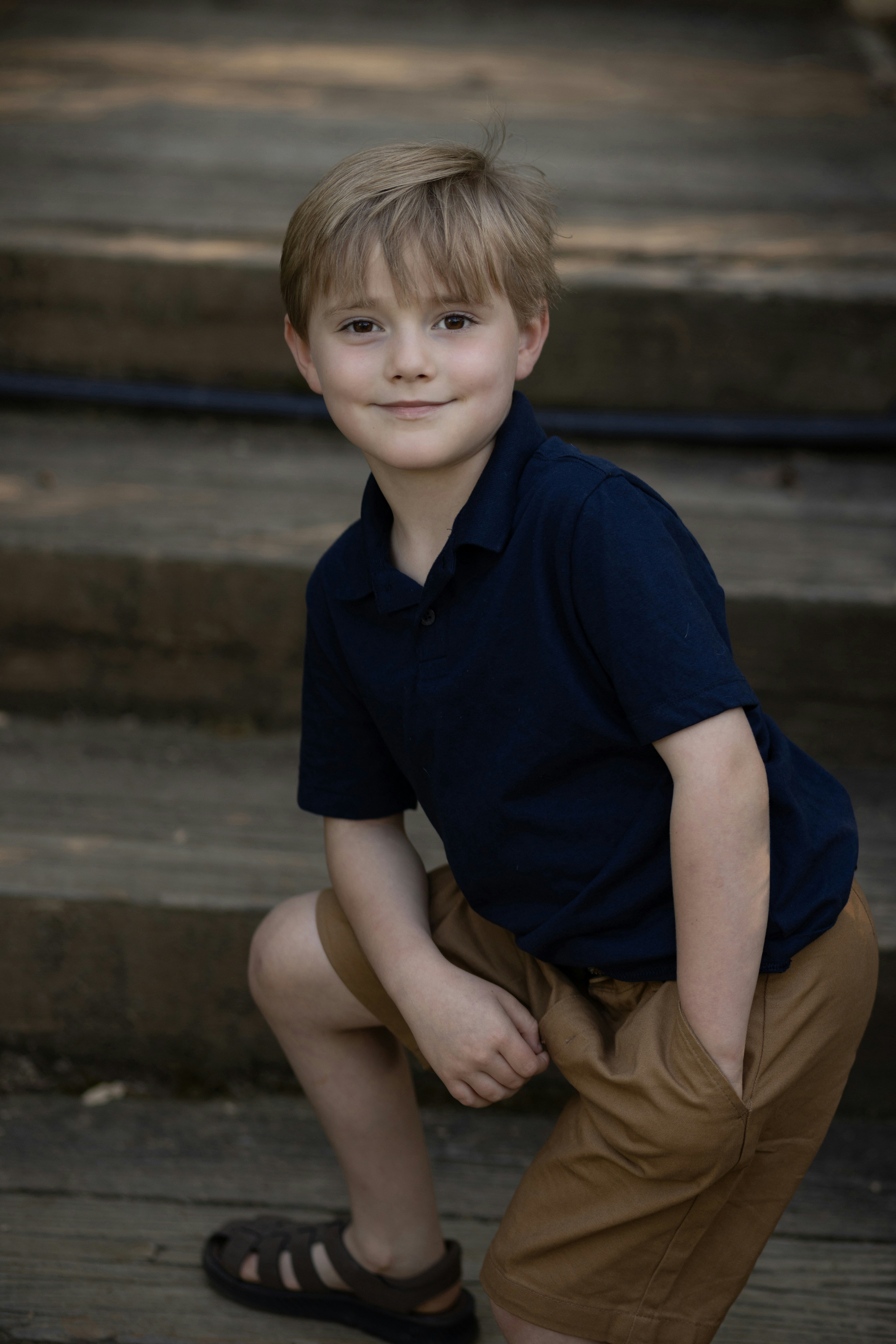 Young explorer on wooden steps, calm smile and navy polo