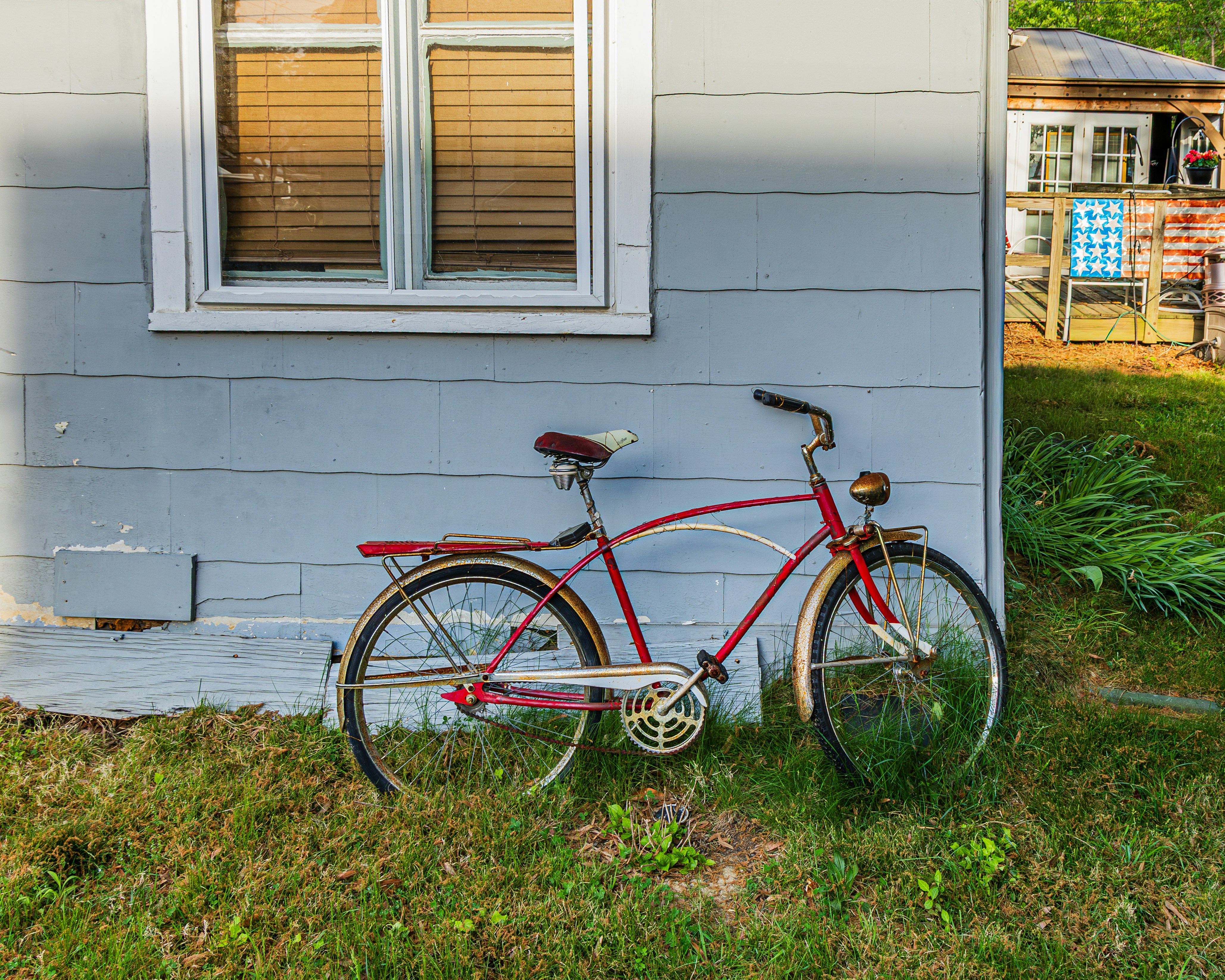 Red Bicycle Resting Against a Weathered House