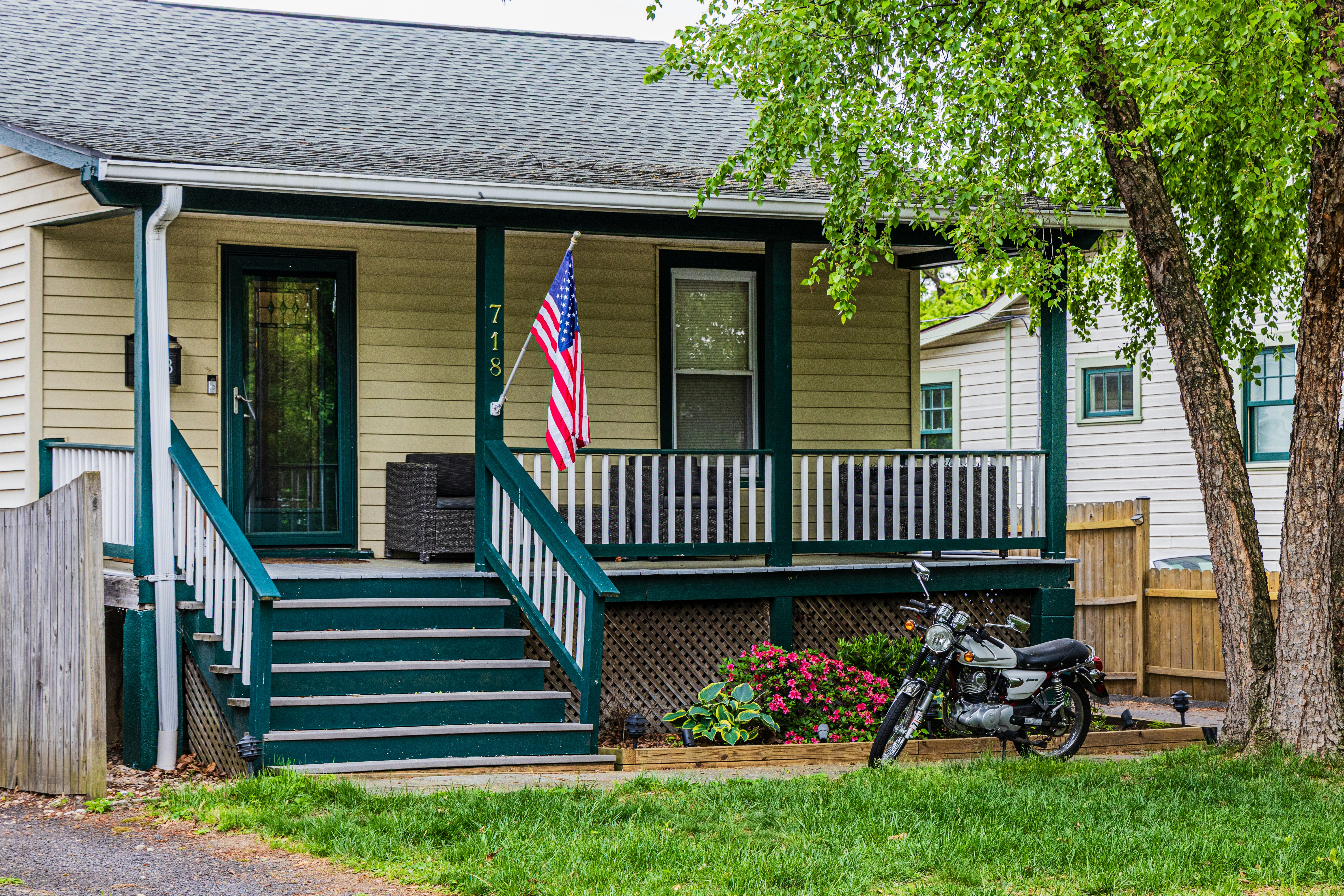 Front Porch Portrait: Flag, Stairs, and a Motorcycle in the Yard