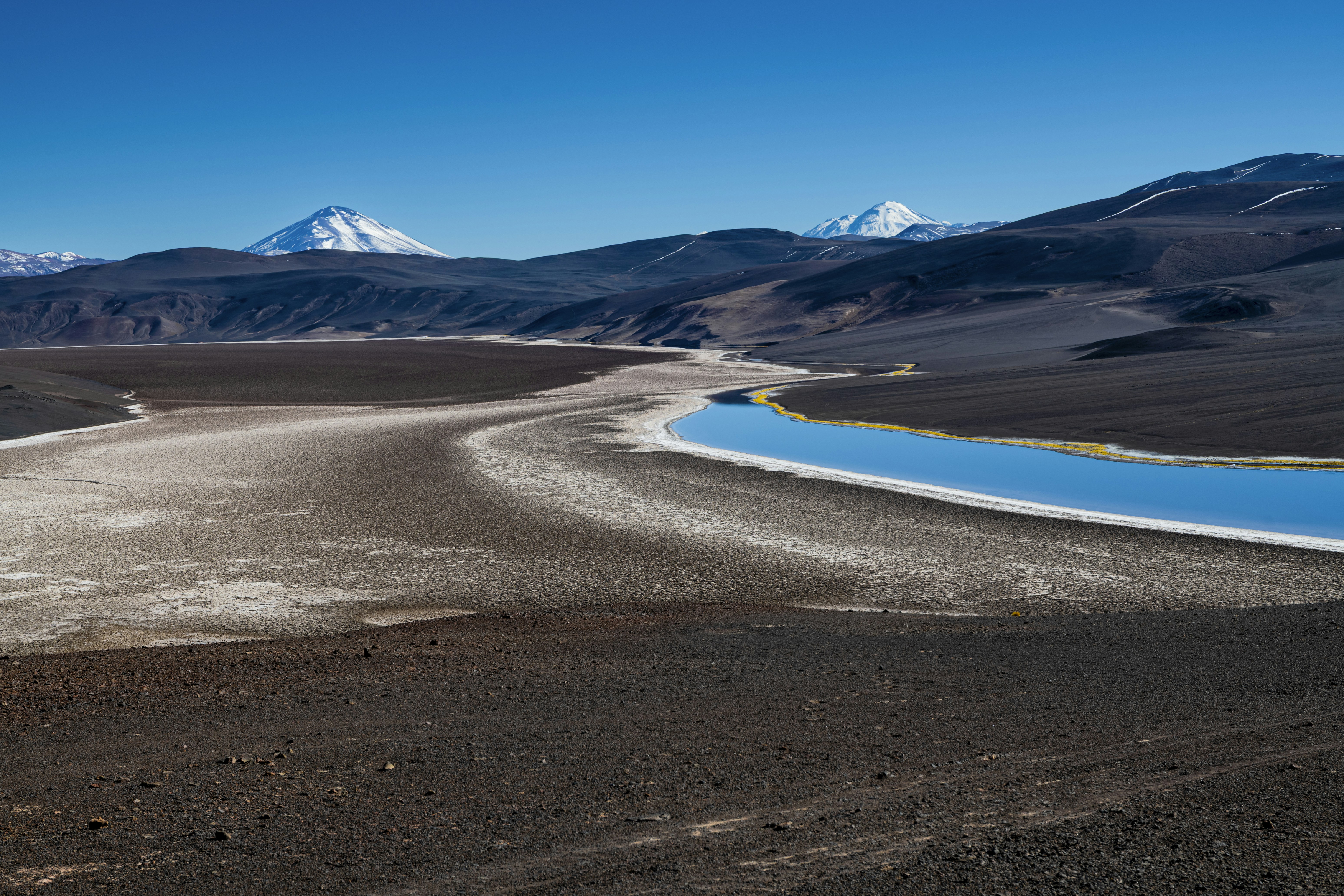 Azure Ribbon: A Curving Stream Winding Through Lunar Contrast